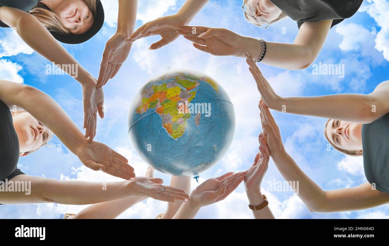Schoolgirls hug the earth globe with their hands, making a circle out ...