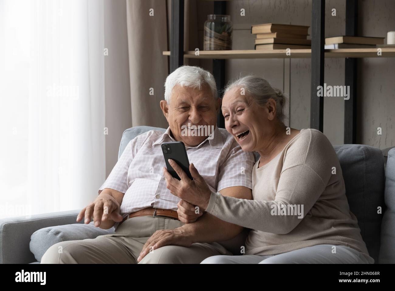 Happy excited older married couple using smartphone Stock Photo - Alamy
