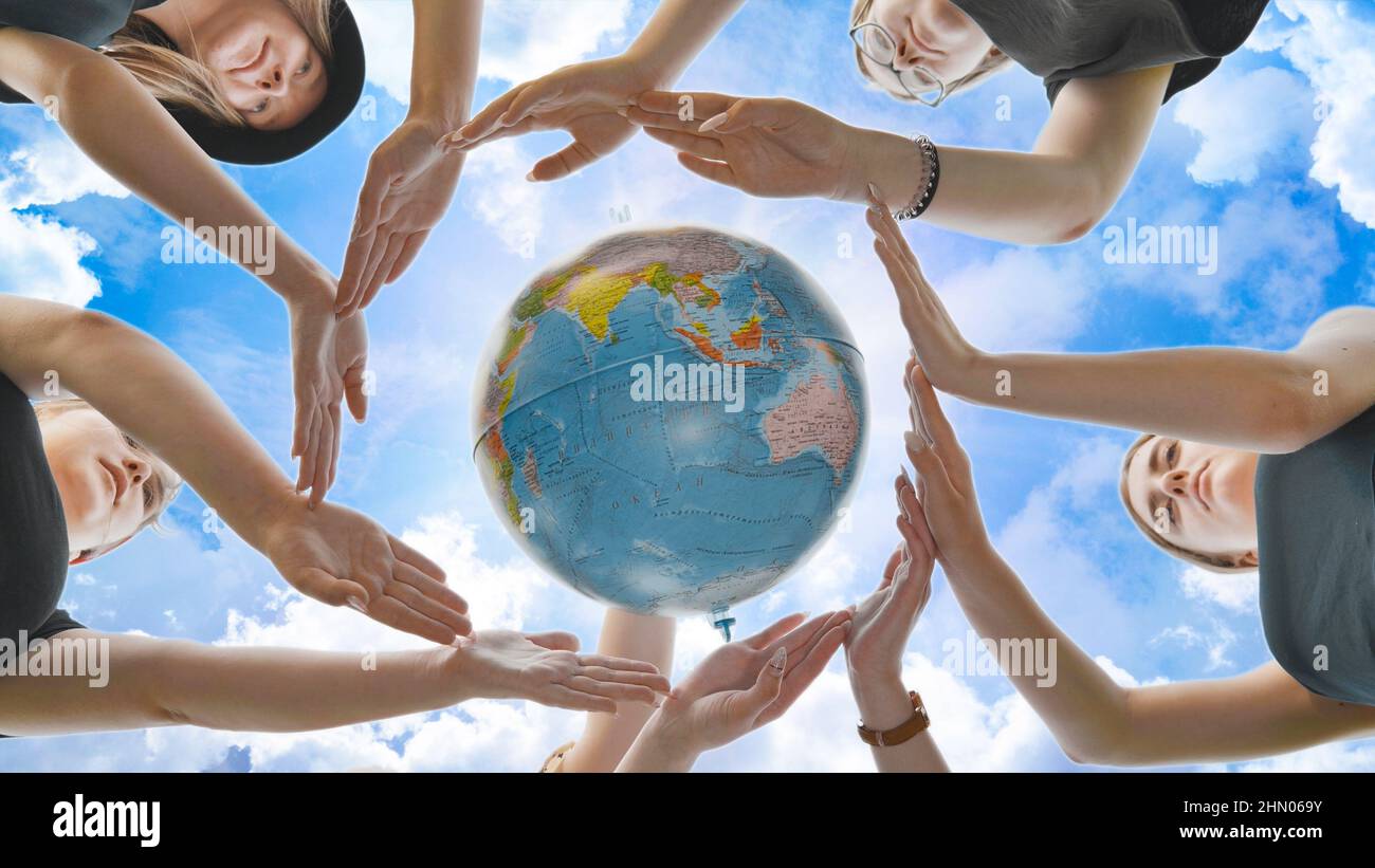 Schoolgirls hug the earth globe with their hands, making a circle out ...