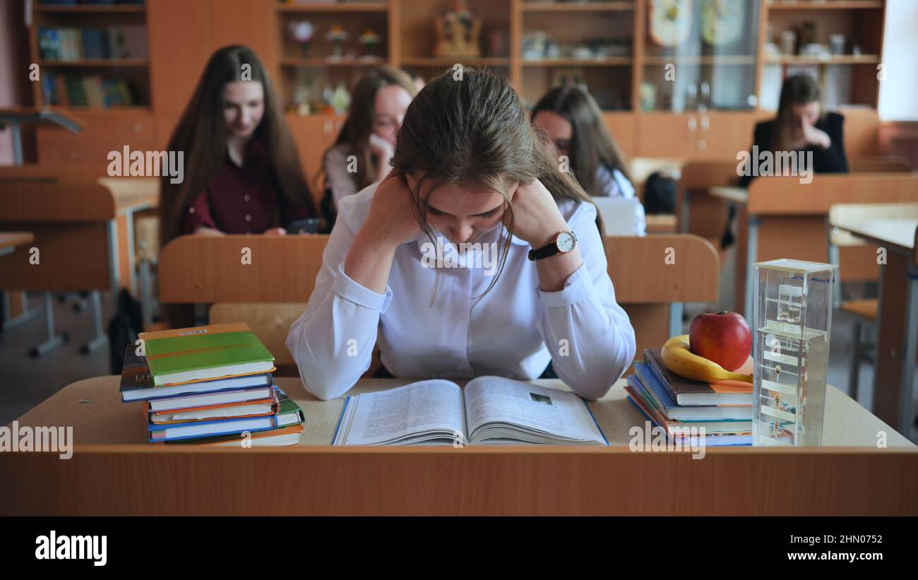 A hardworking student sits at a desk with books at school Stock Photo ...