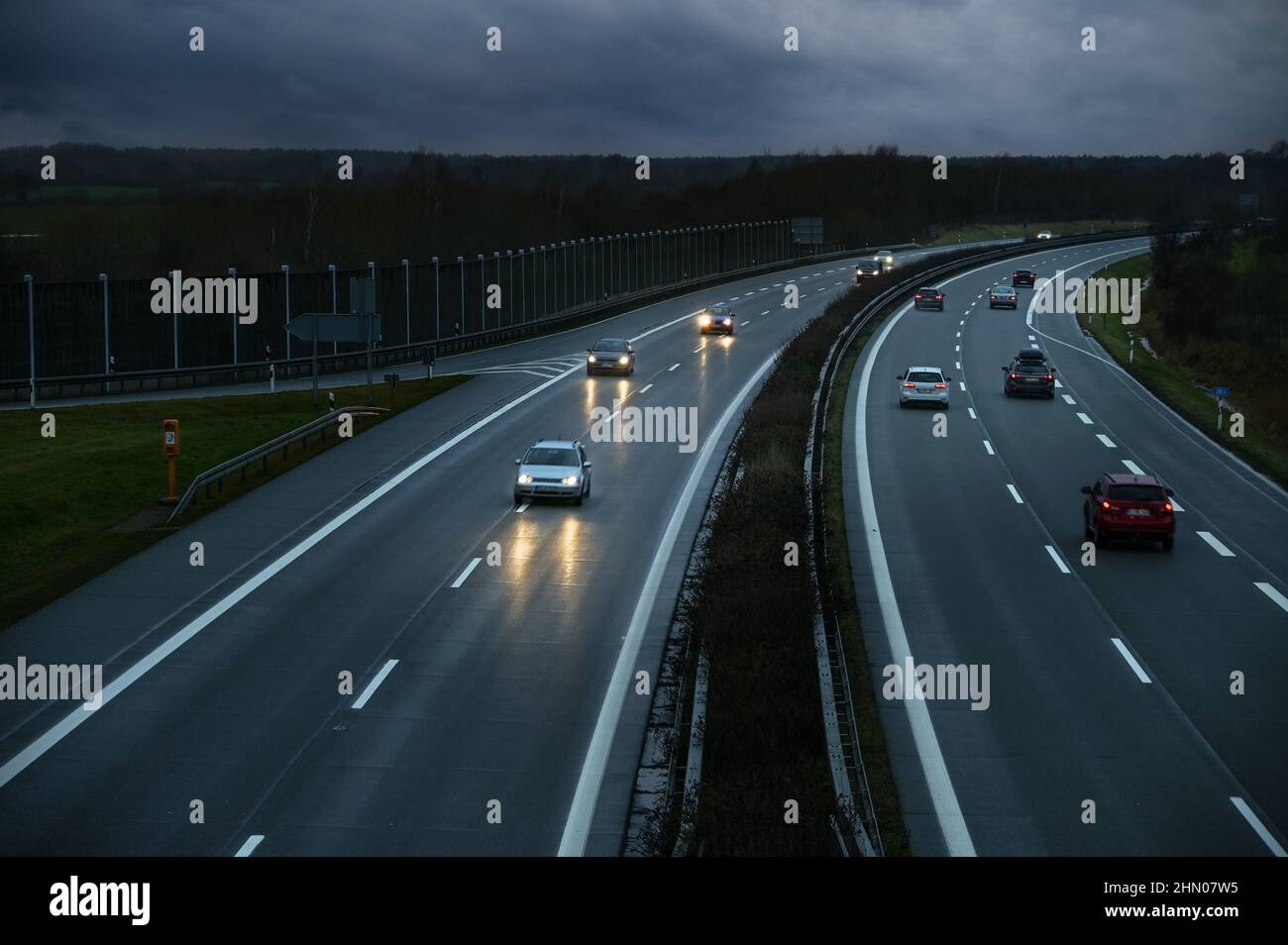 Driving cars on a wet highway at dusk under a cloudy sky in Germany ...