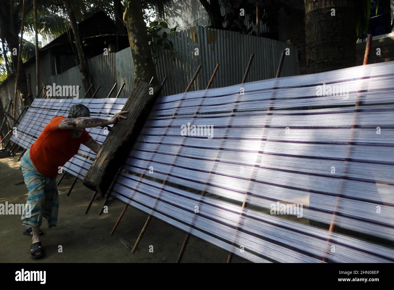 FEBRUARY 13,2022,DHAKA,BANGLADESH-Workers prepare yarn to make cloth with yarn in a backyard ...