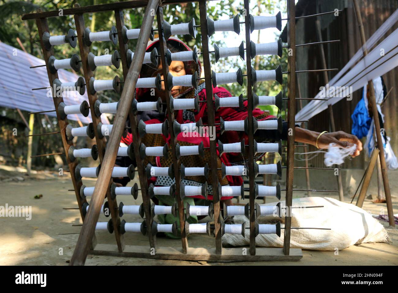 FEBRUARY 13,2022,DHAKA,BANGLADESH-Workers prepare yarn to make cloth with yarn in a backyard ...