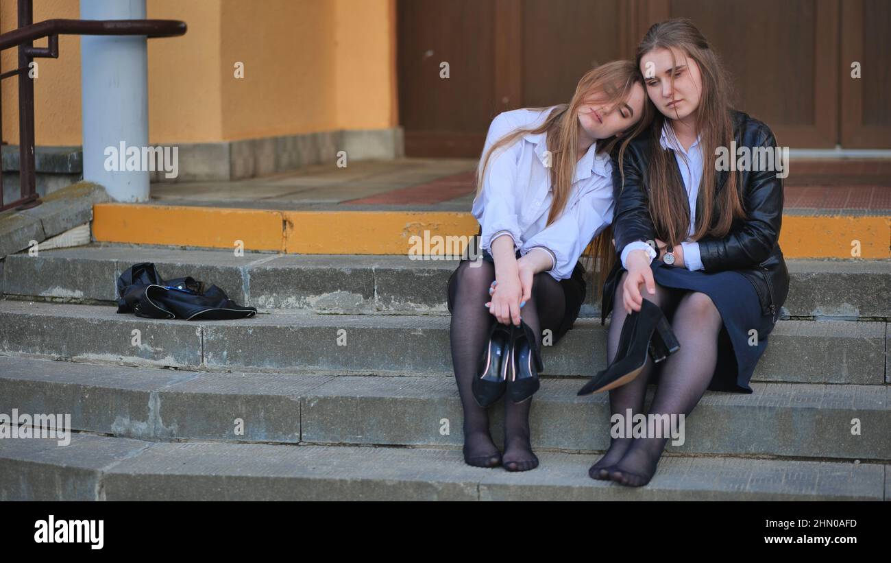 Tired schoolgirls sit barefoot on the steps of the school Stock Photo ...