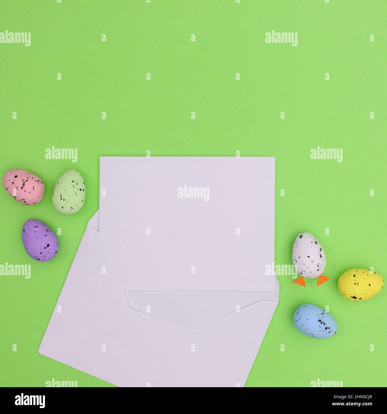 Paper card note in envelope and colorful vibrant eggs around on bright ...