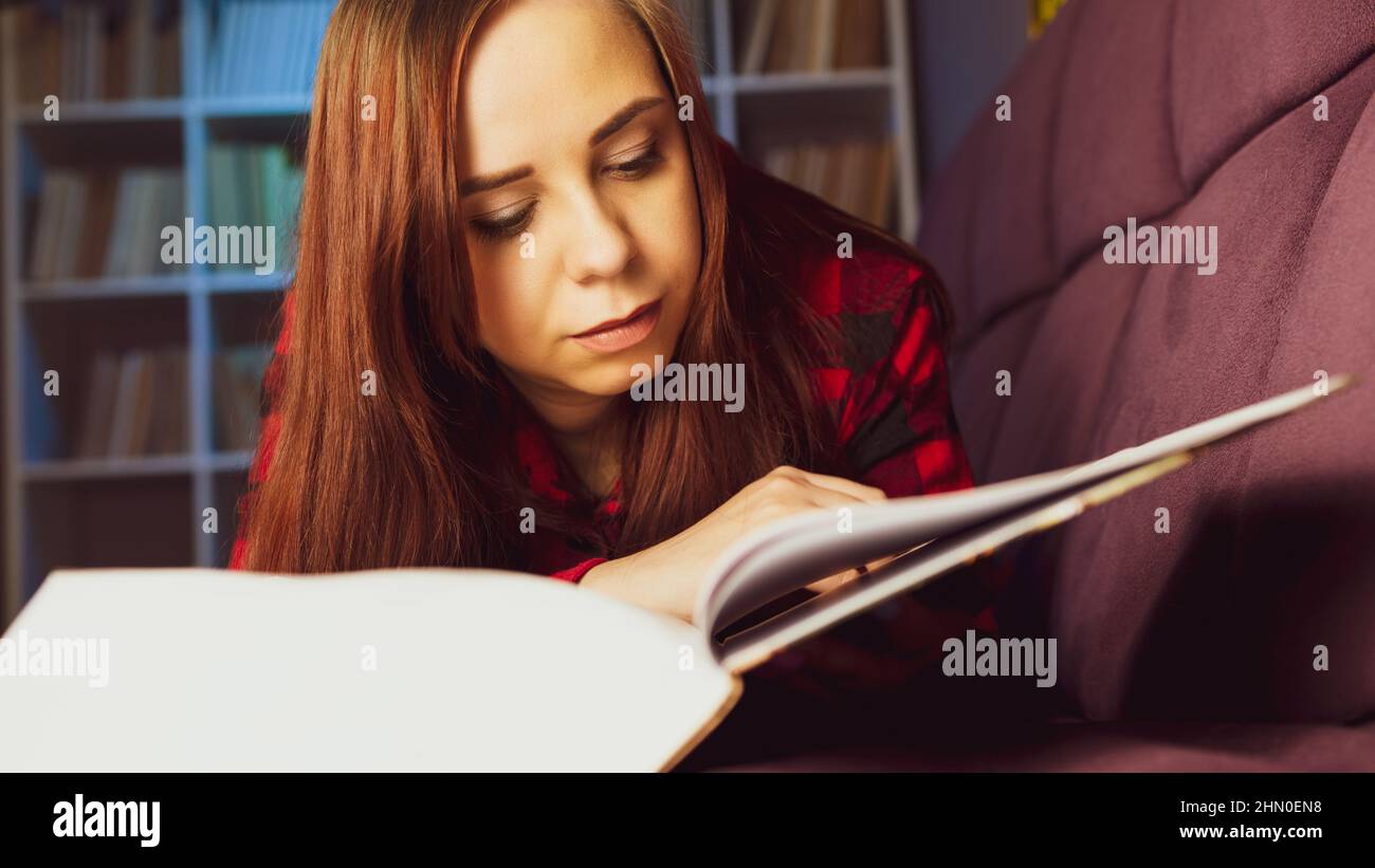 A beautiful student reading a big book. A thoughtful young woman lying ...