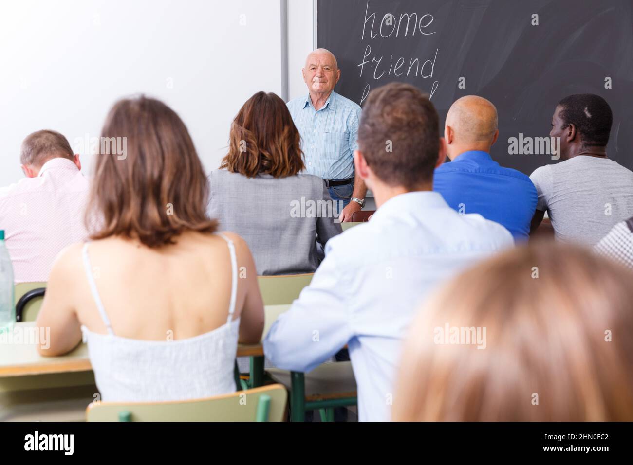 Mature teacher standing in front of students Stock Photo - Alamy