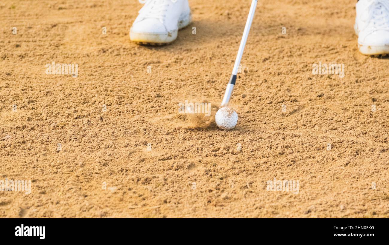 Close-up of a person hitting the golf ball in a sand bunker. golf ...
