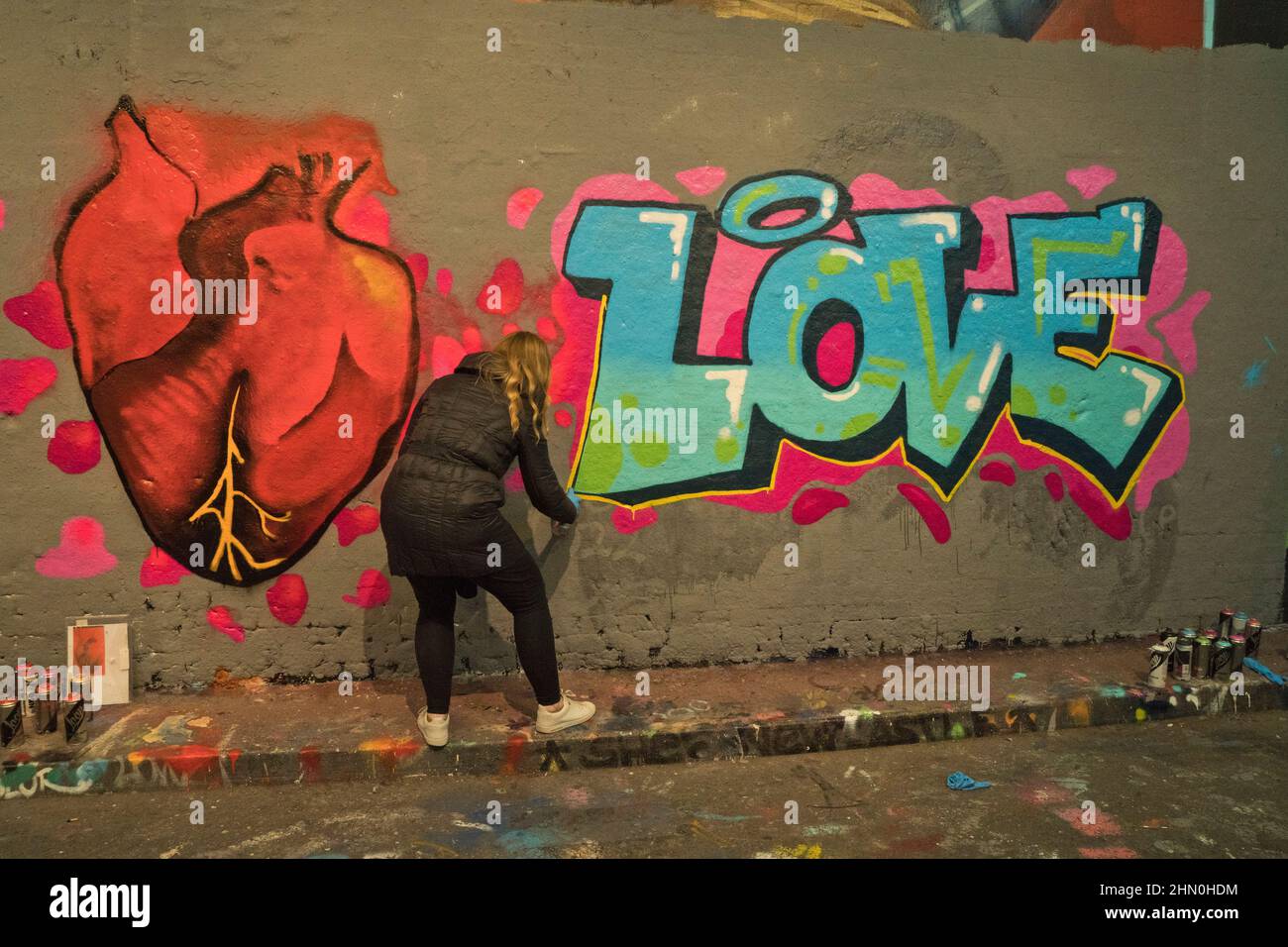 Graffiti artist painting a heart and 'love' sign message to celebrate ...