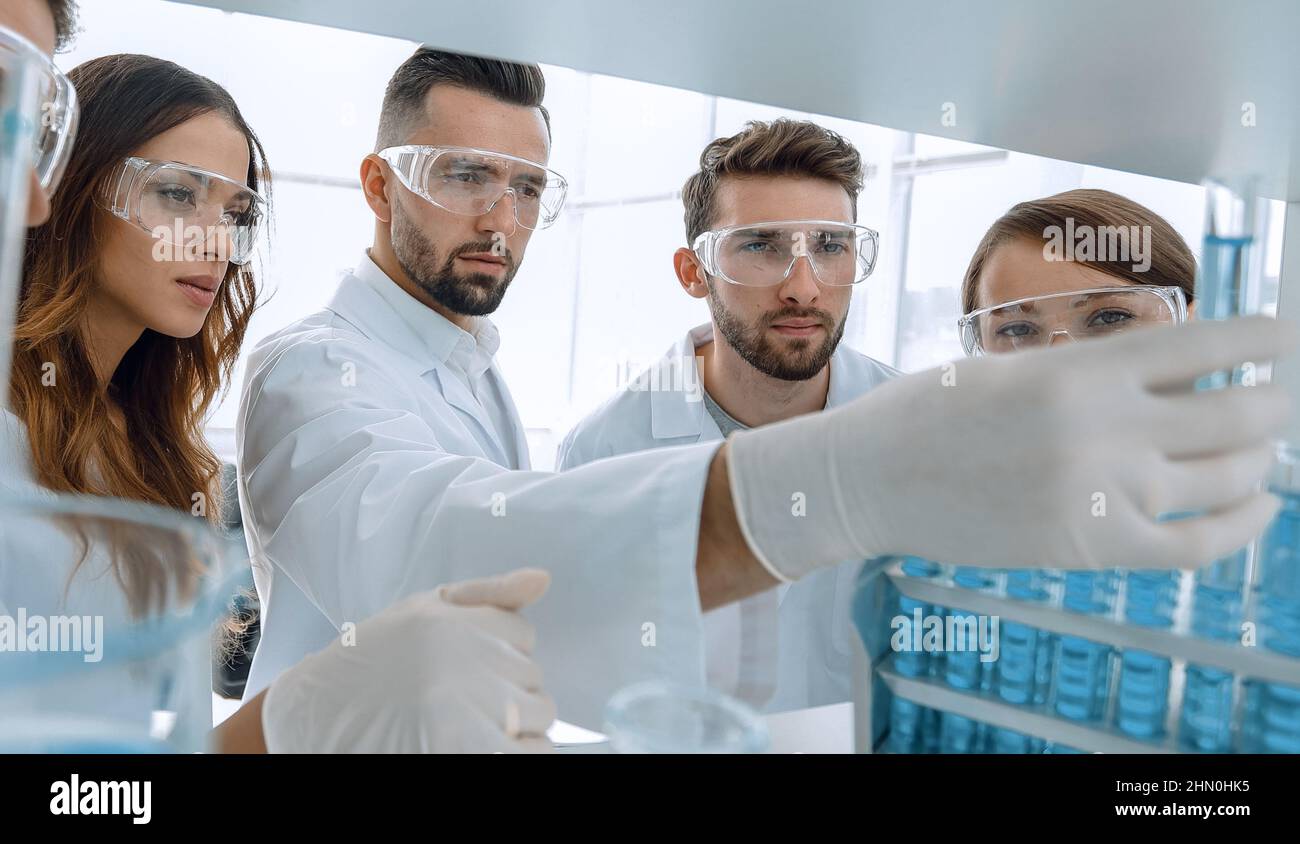 background image is a group of microbiologists studying the liqu Stock ...