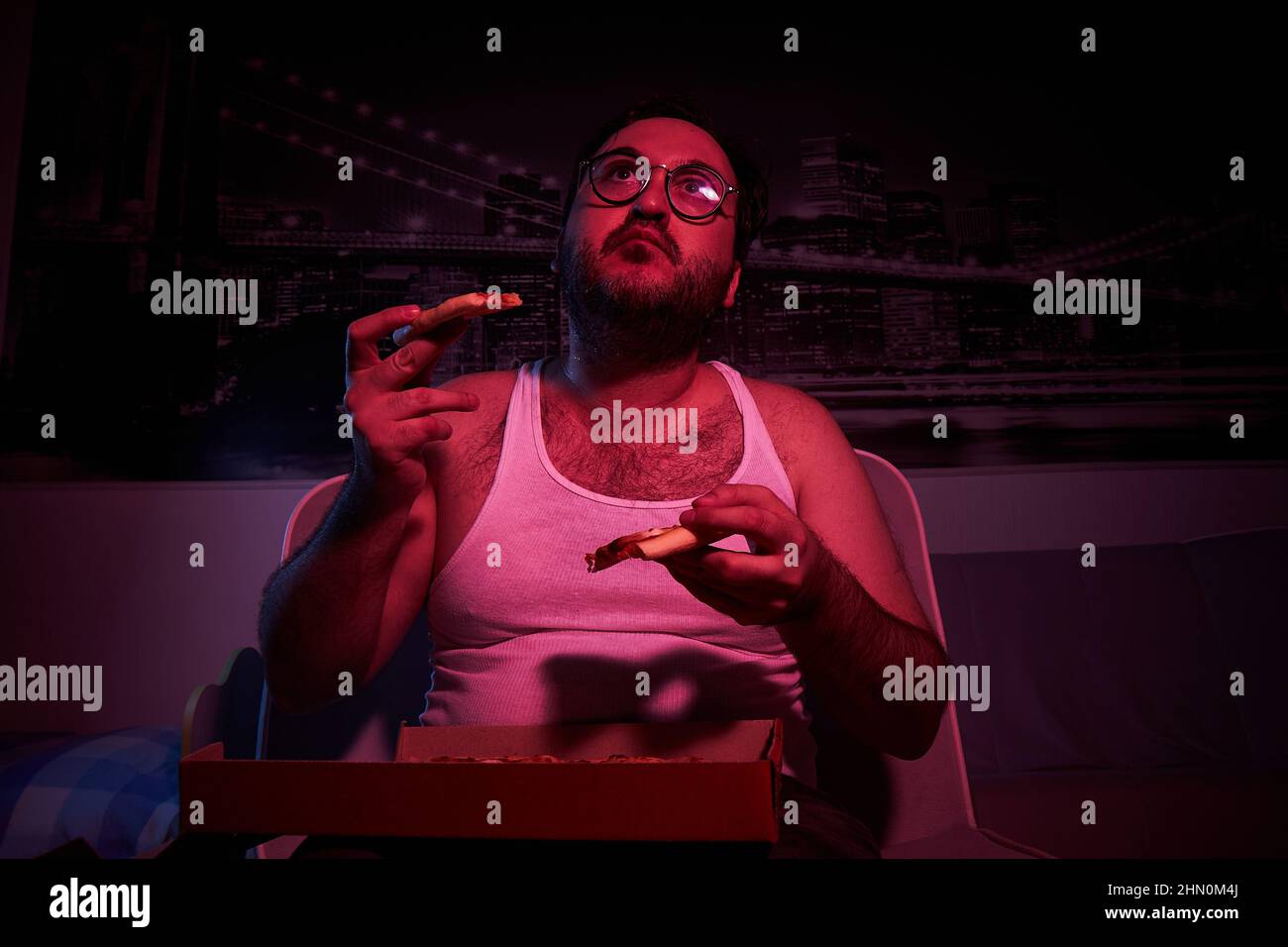 A 40-year-old unshaven overweight man watches TV, shows various ...