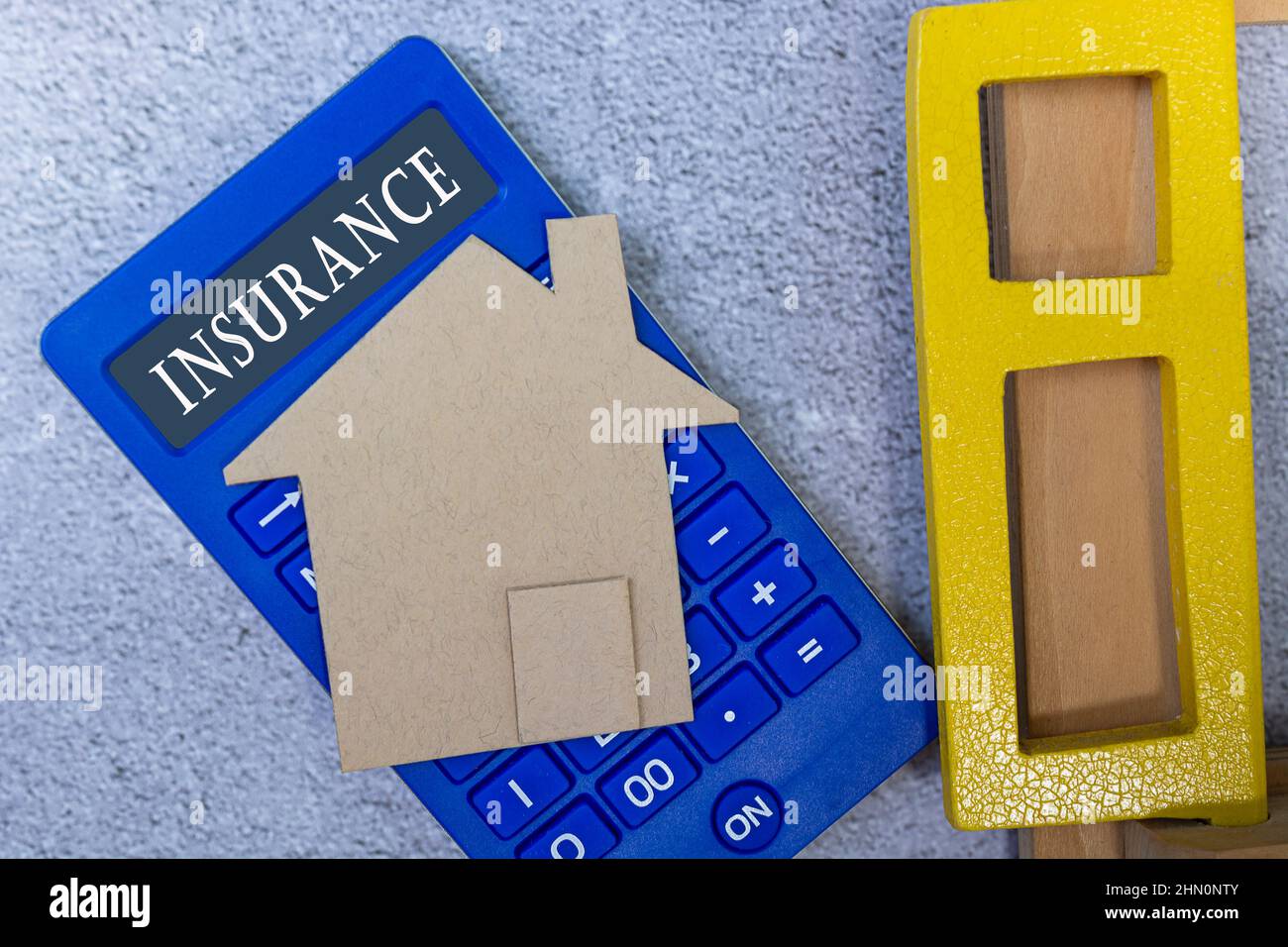 Insurance text on calculator with paper house model and window frame on ...