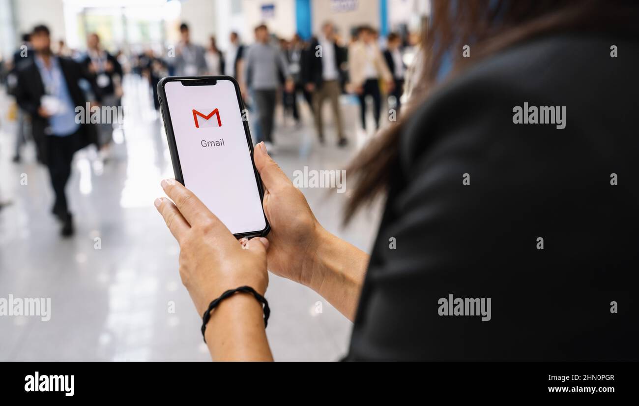 Business woman holding a iPhone with Google Gmail app logo on the display. Gmail is a most ...