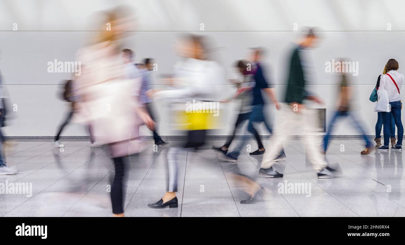 Anonymous crowd of business people go through aisle at a trade fair ...