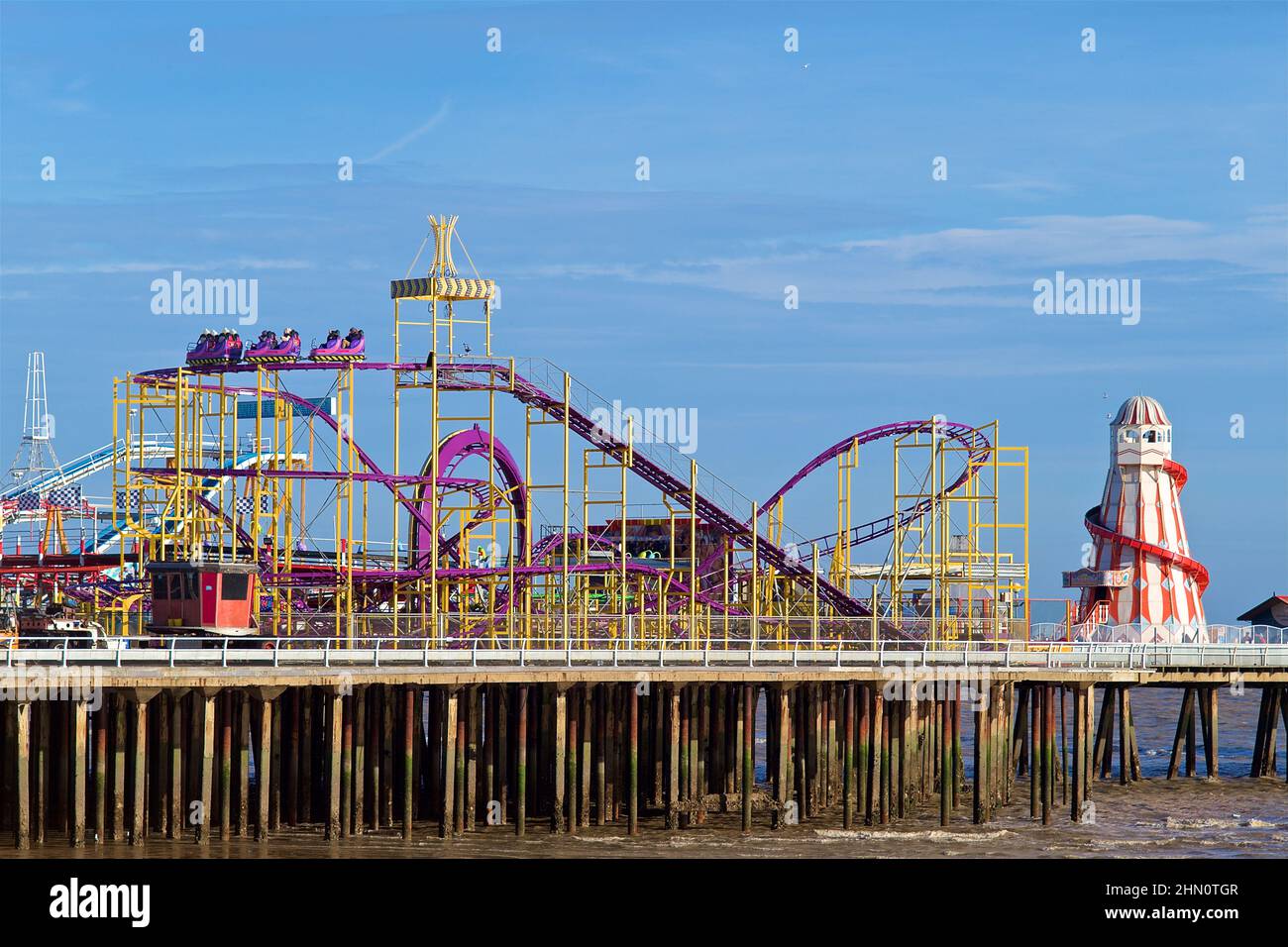 Clacton pier funfair with a roller coaster and helter skelter amongst ...