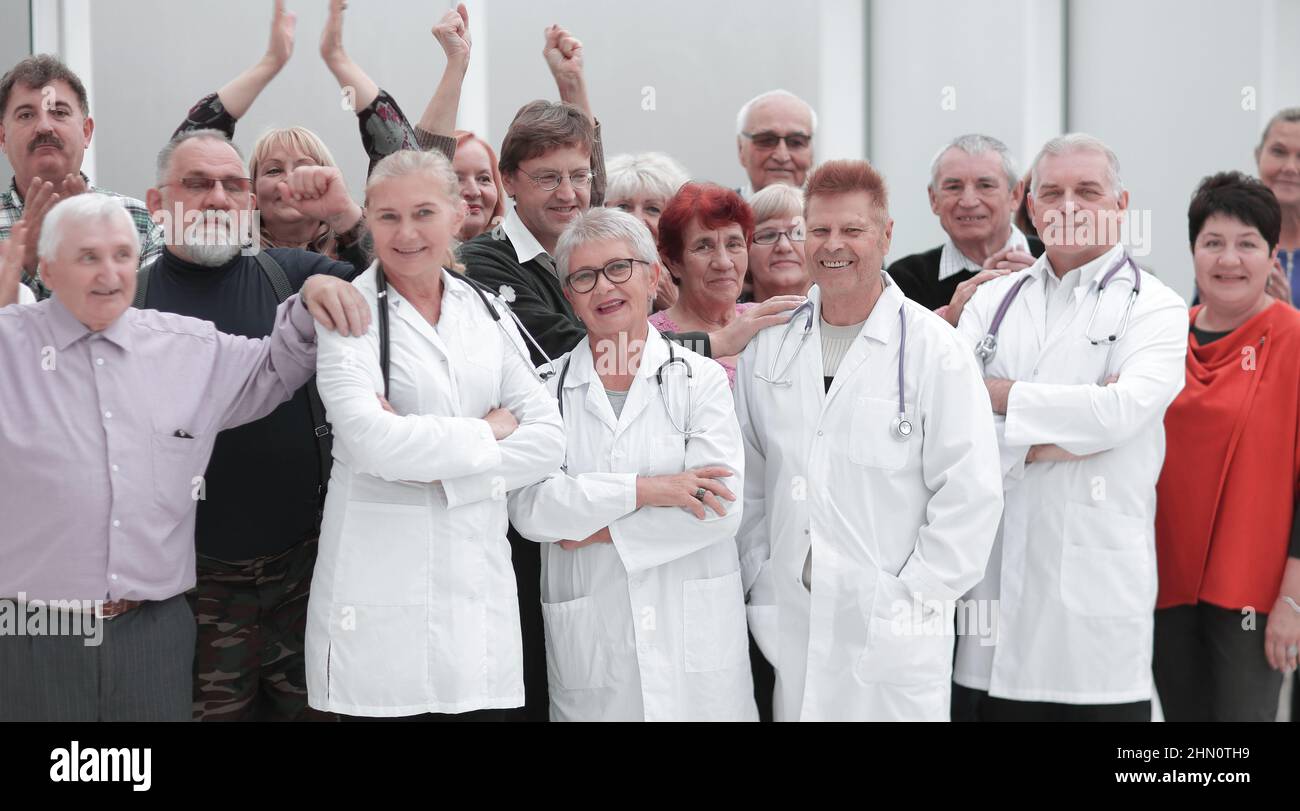 Happy doctors standing in corridor with team at hospital with crossed ...