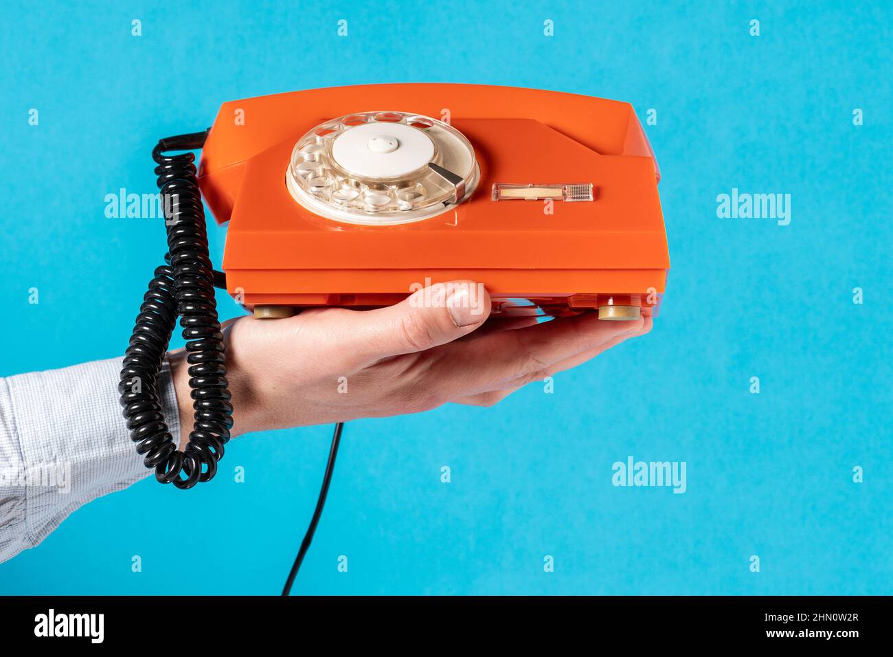 Hand with old rotary telephone over blue background.Communication ...