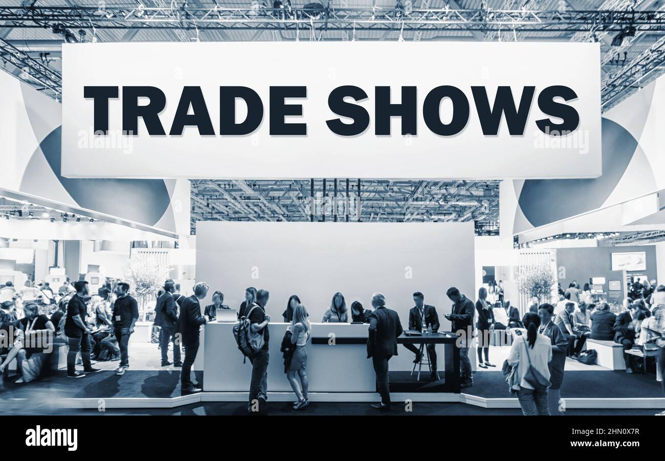 Crowd of people at a trade show booth with a banner and the text Trade ...