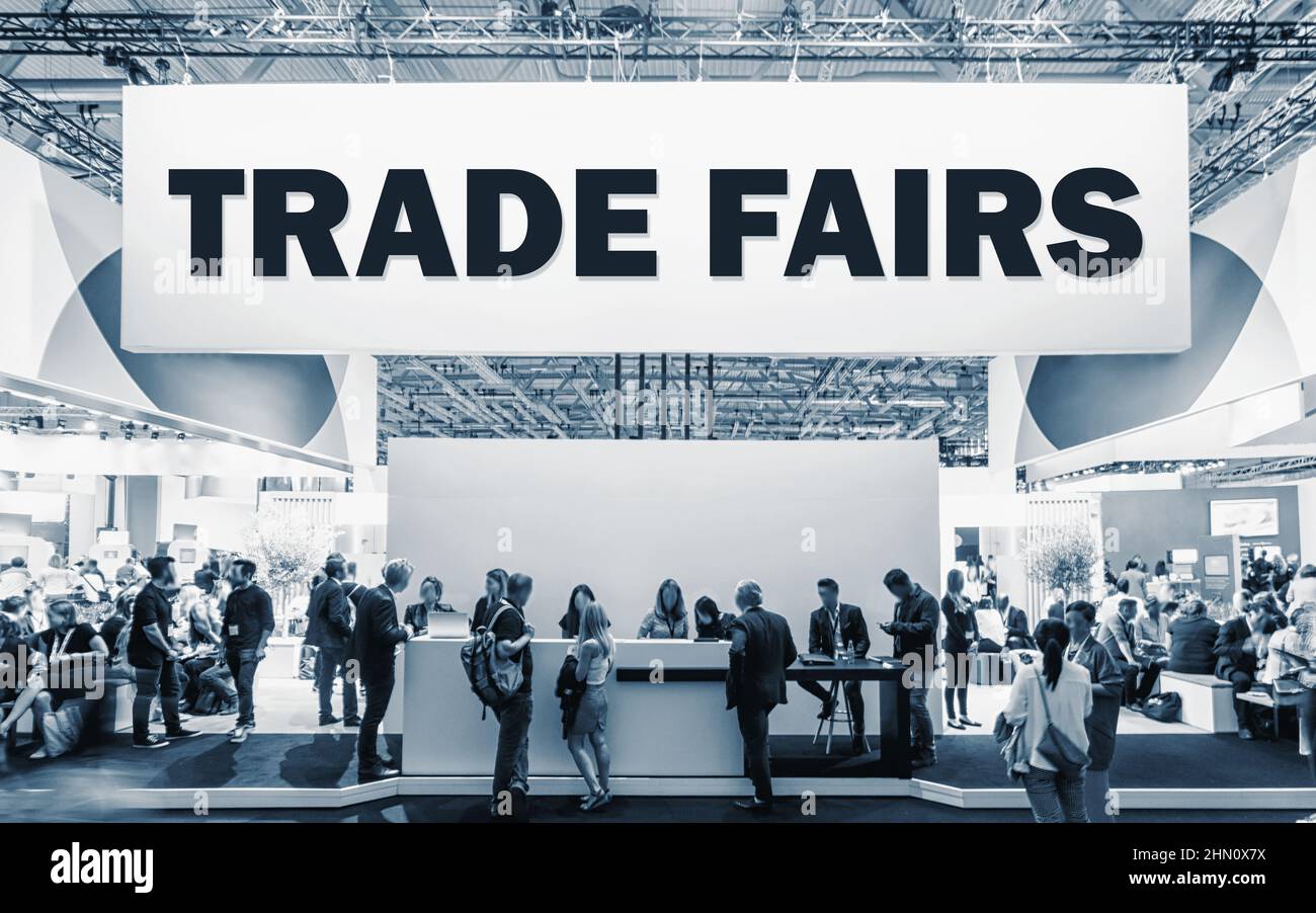 Crowd of people at a trade show booth with a banner and the text Trade ...