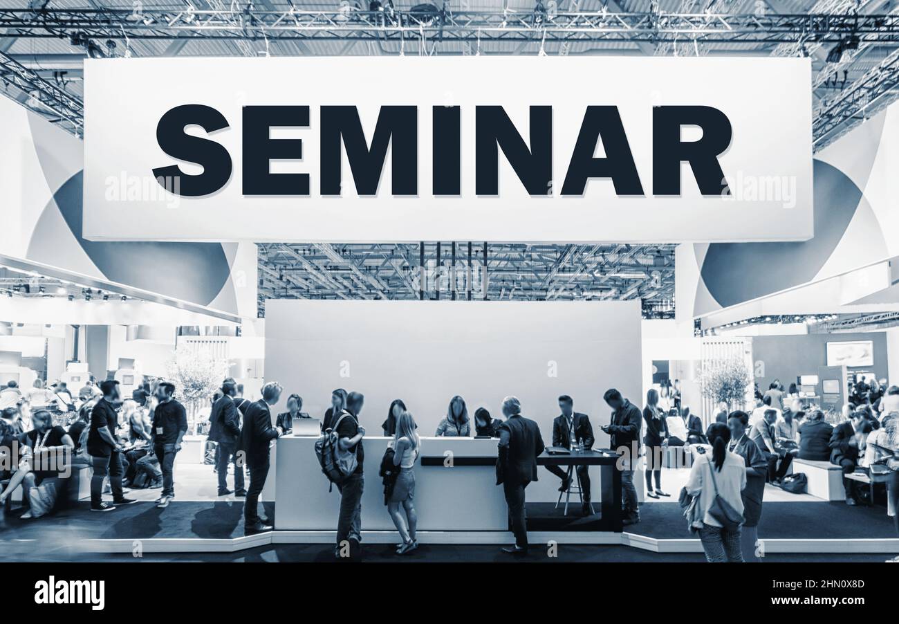 Crowd of people at a trade show booth with a banner and the text ...