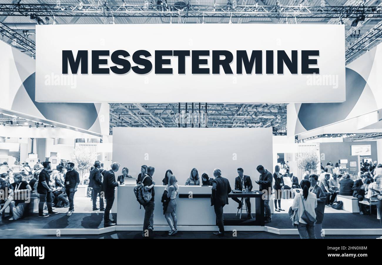 Messetermine. Crowd of people at a trade show booth with a banner and ...