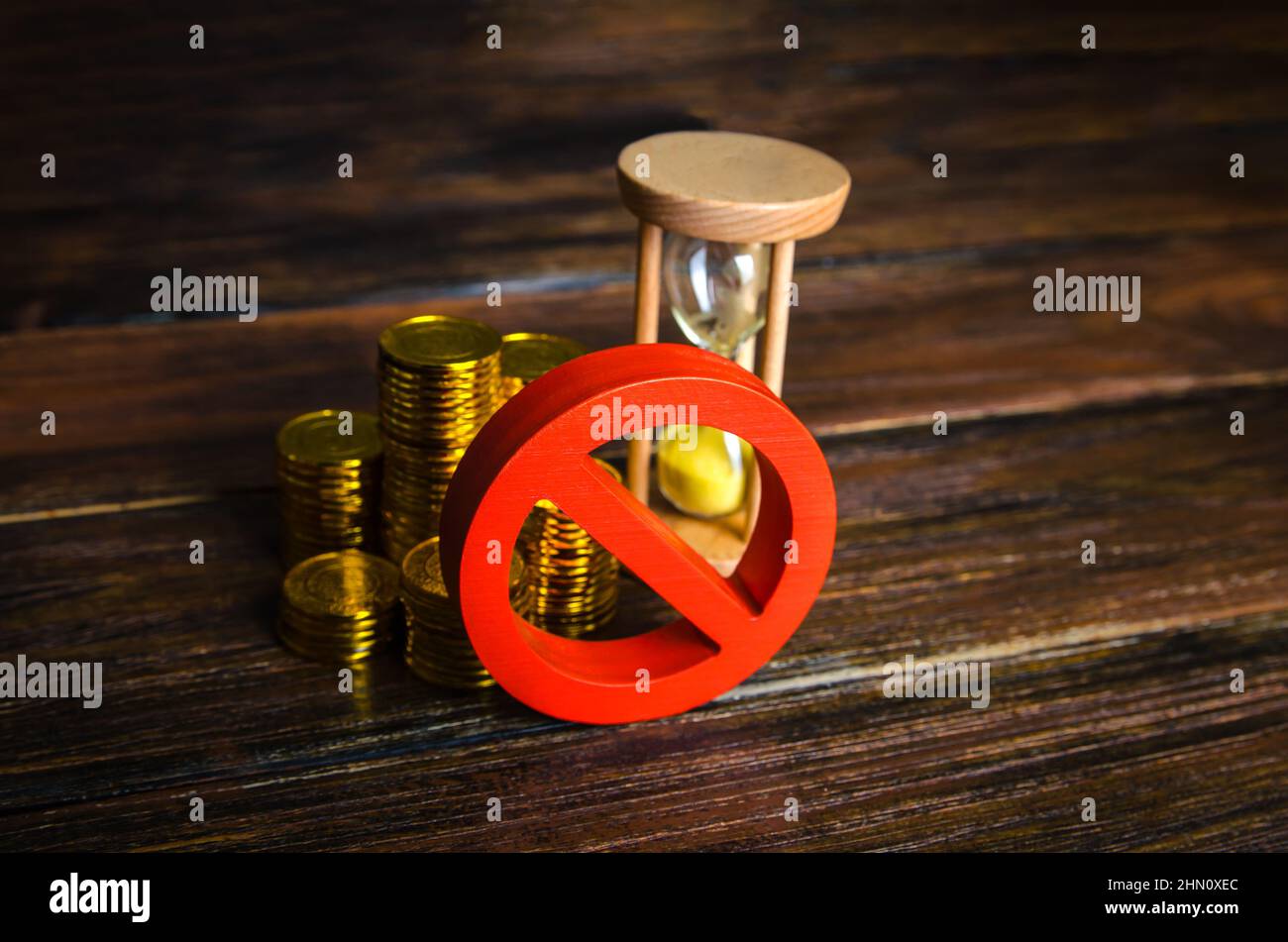 Money and hourglass under the prohibition sign. Sanctions and ...