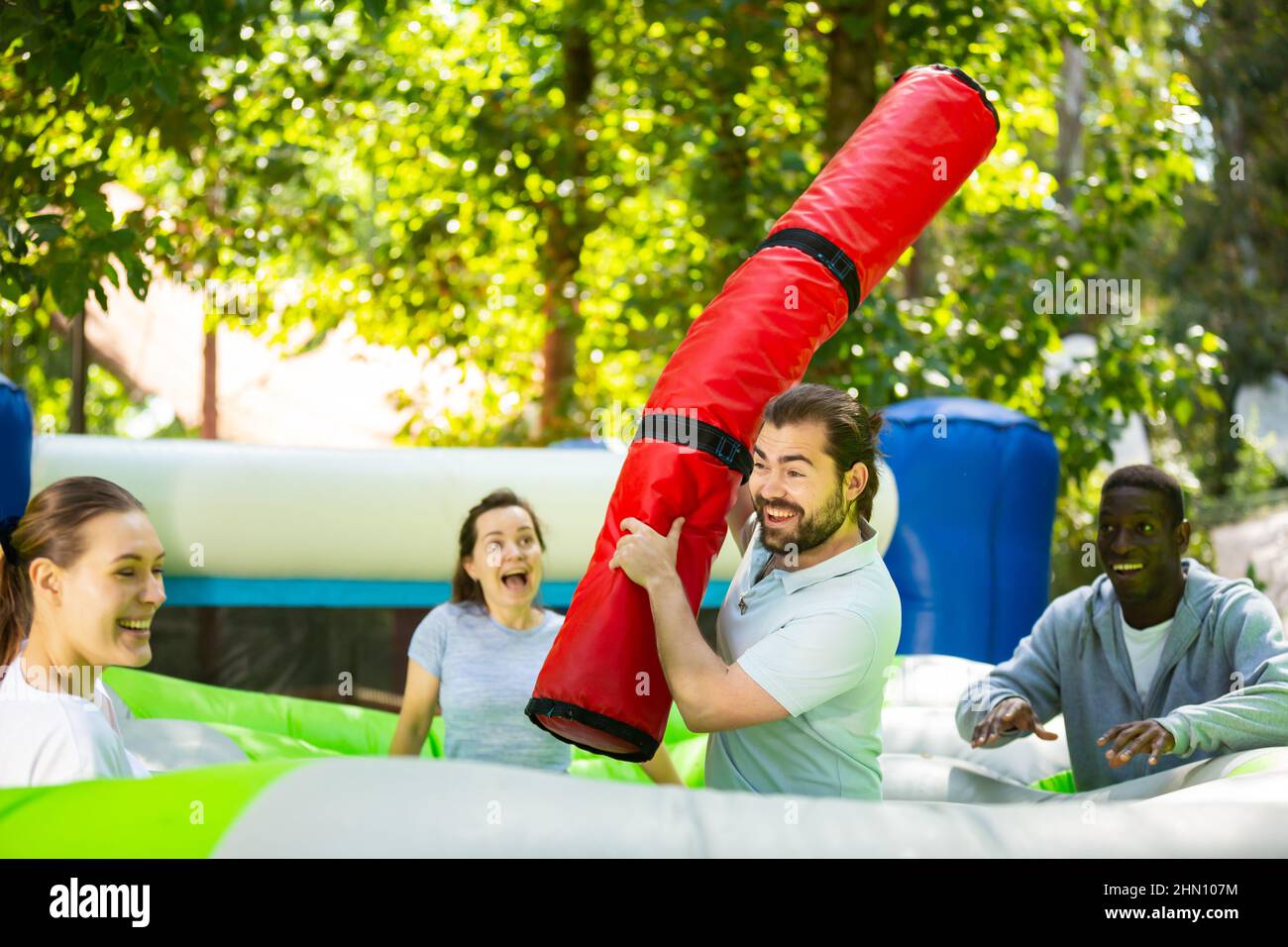 Funny friends playing on an inflatable trampoline in an amusement park ...