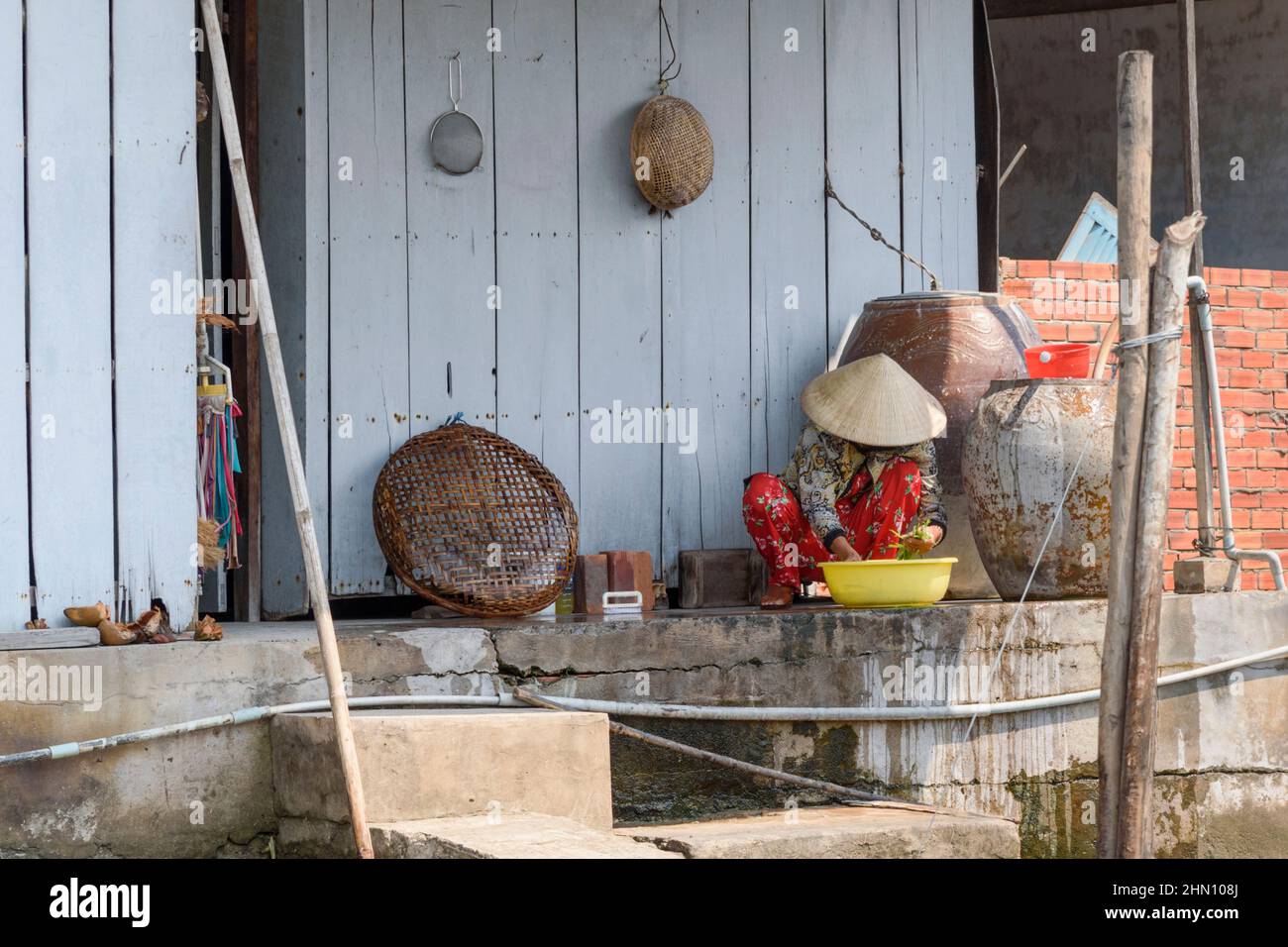A Vietnamese woman prepares food outside her house on the Mekong River ...