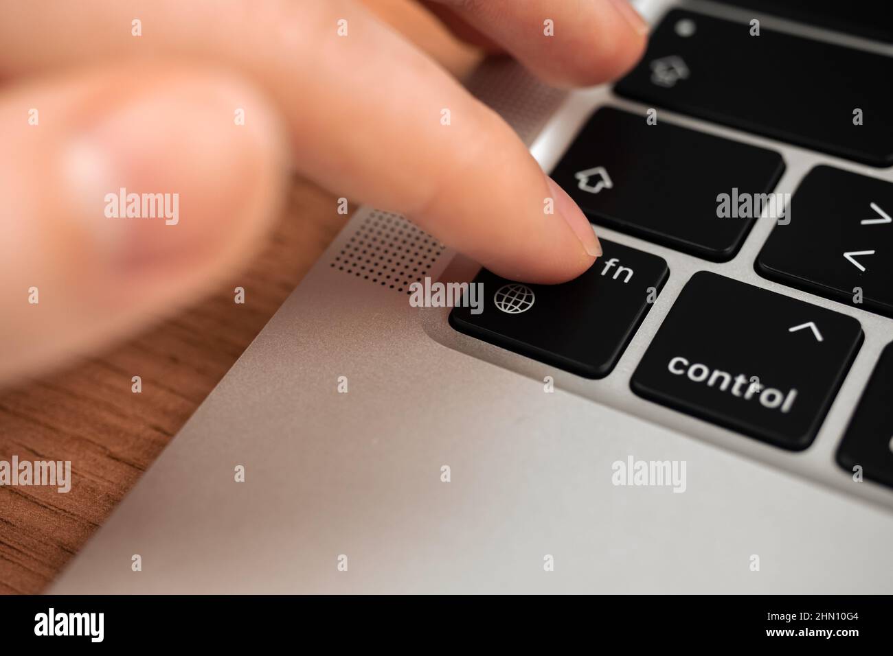 Hand pressing the globe key on modern laptop keyboard. The globe sign ...
