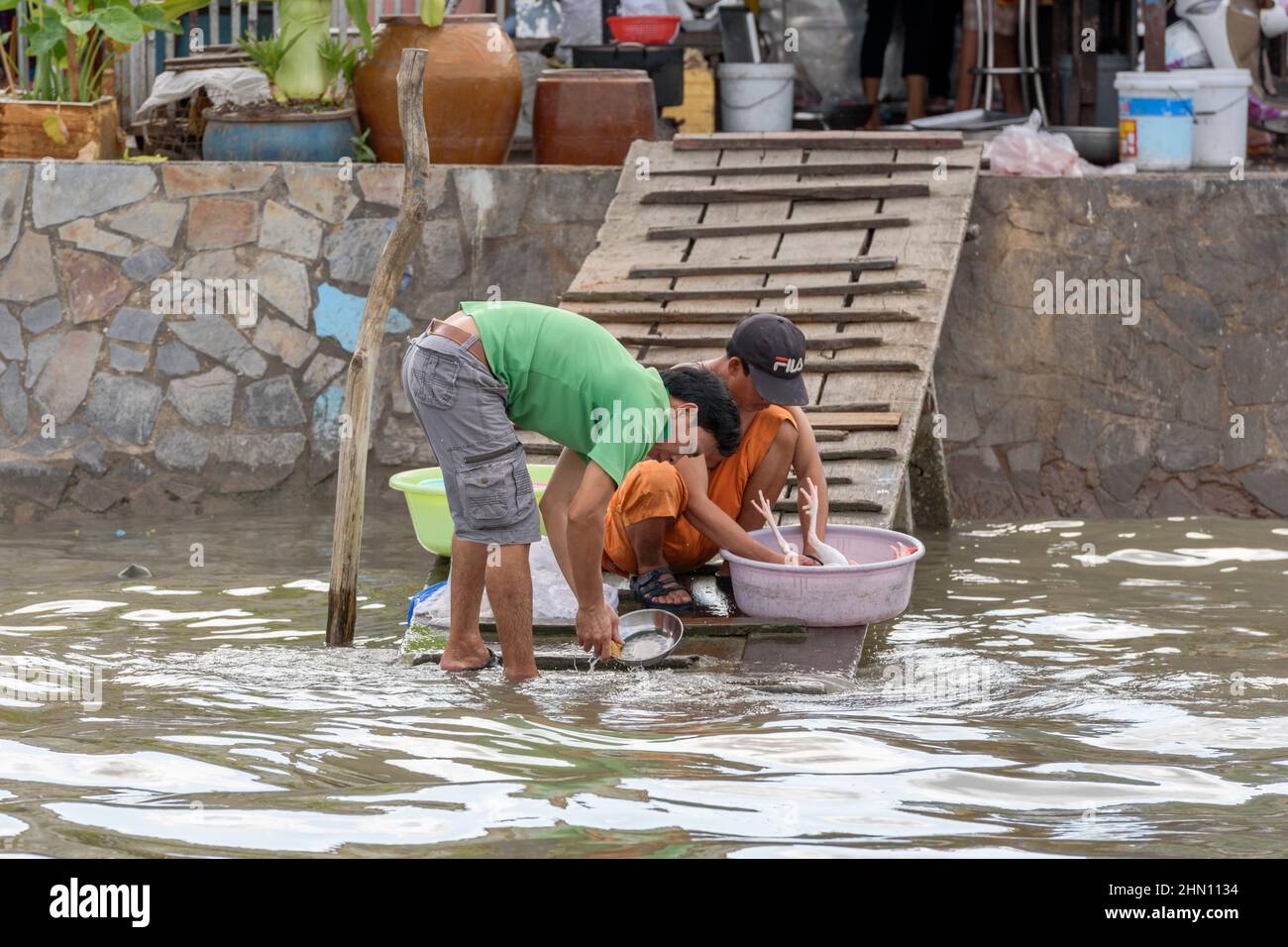 Two young Vietnamese men wash a chicken carcass in the Mekong River at ...