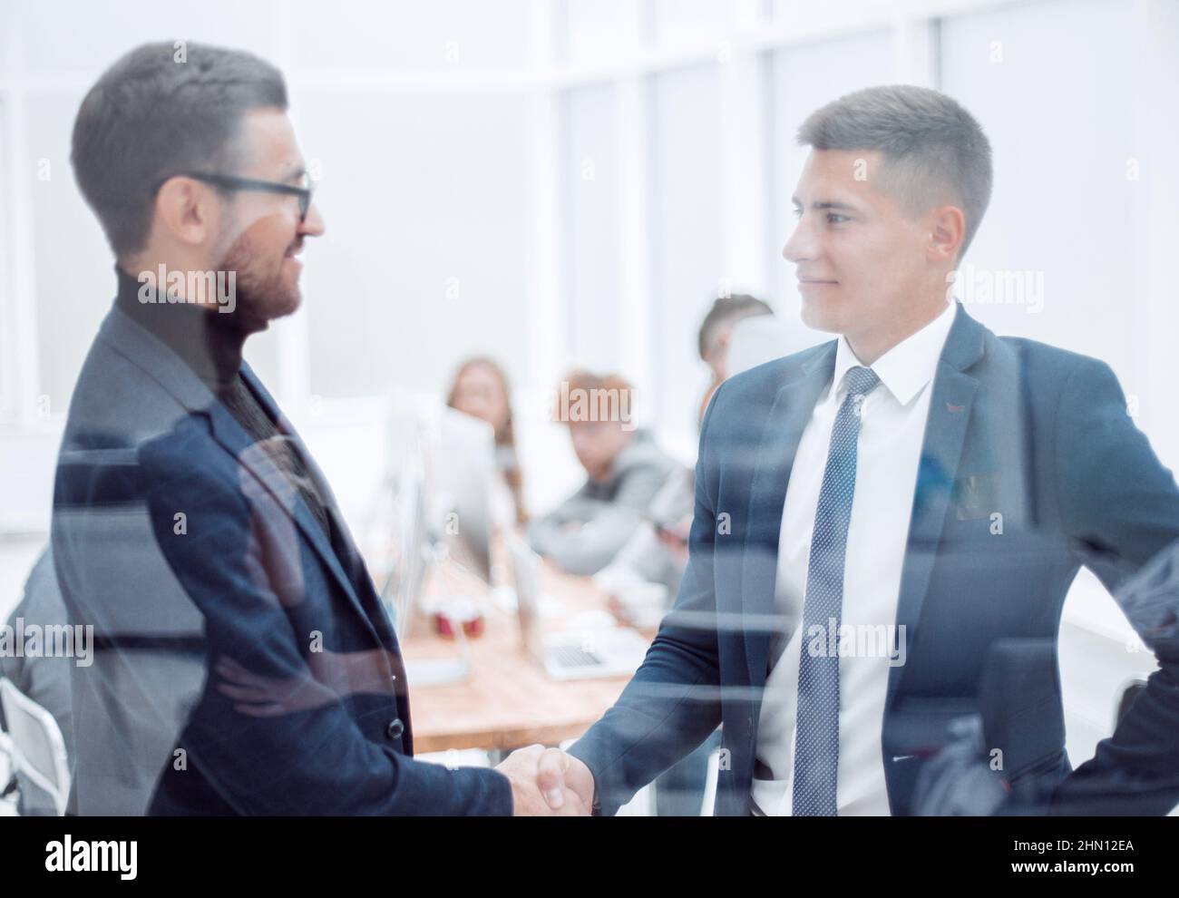 through the glass. business partners handshake in the office Stock ...