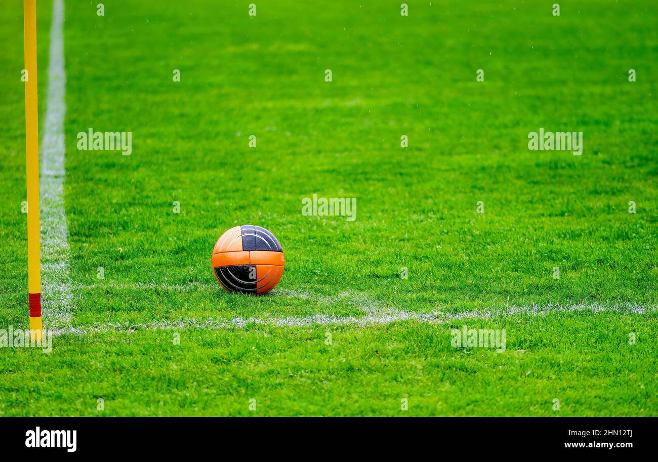 Traditional orange soccer ball on soccer field at the corner pitch ...