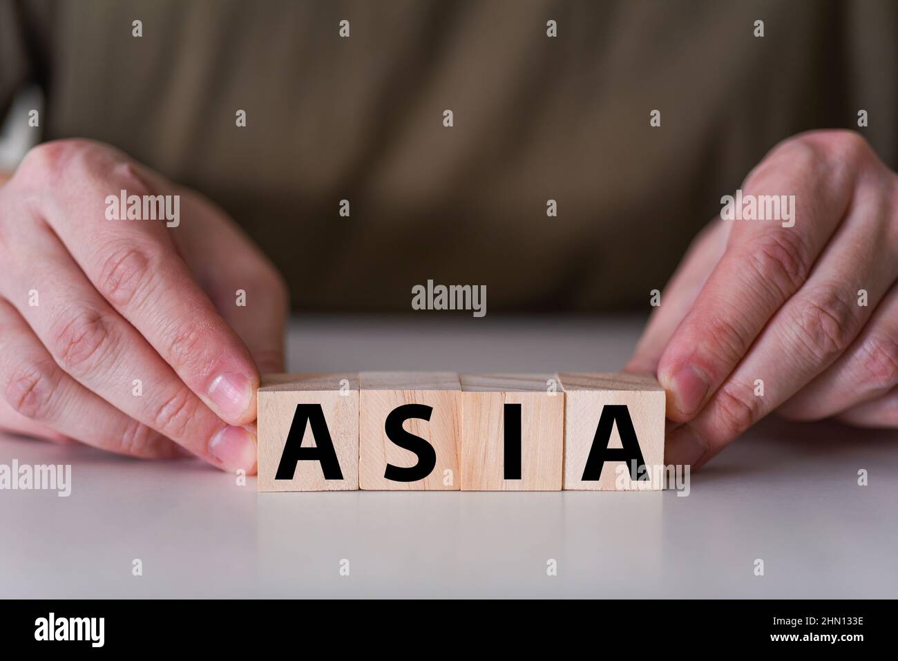 A businessman holds wooden cubes with the word Asia. This rare word is ...