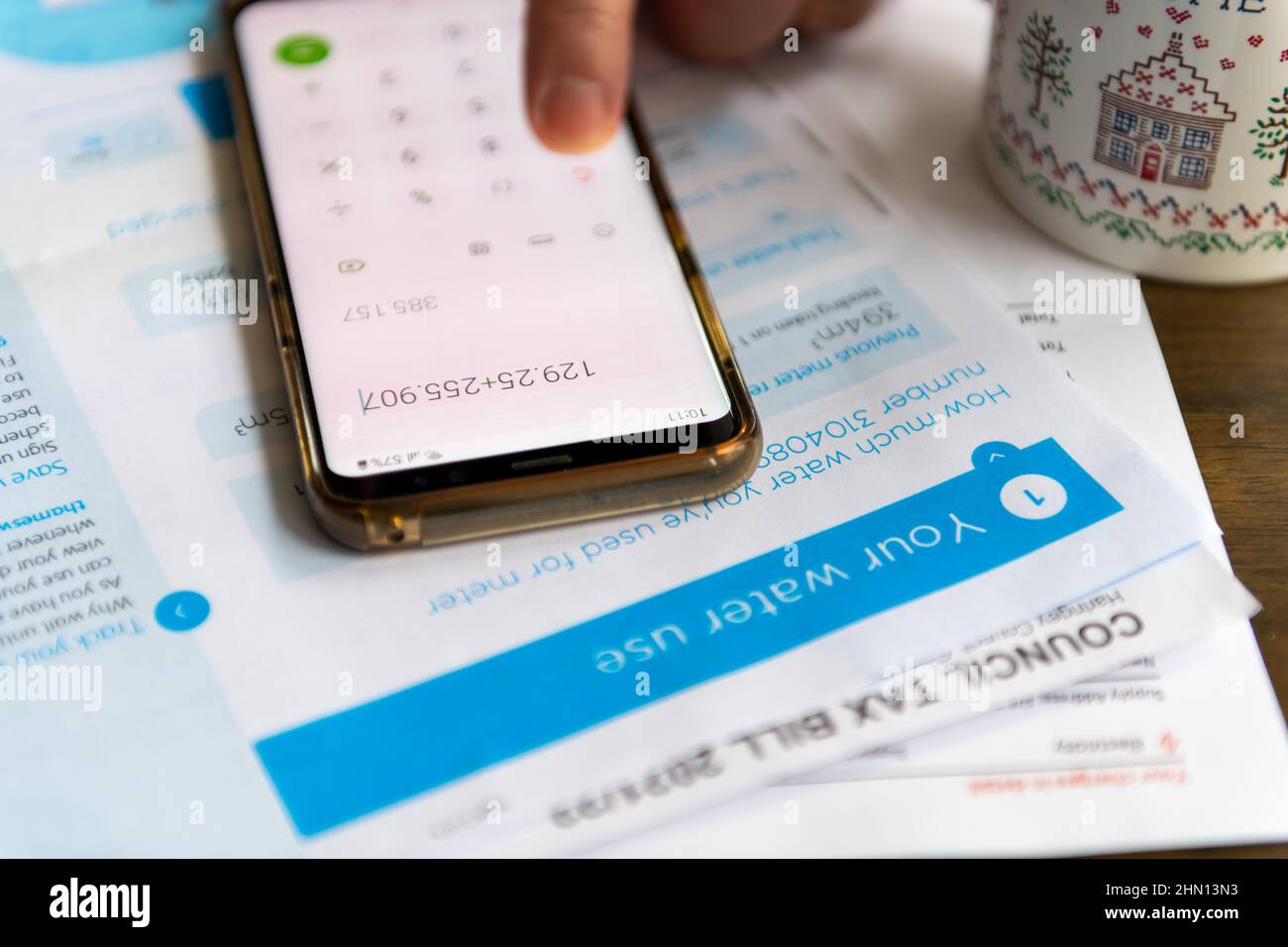 A person using a phone calculator to work out cost of utility and tax ...