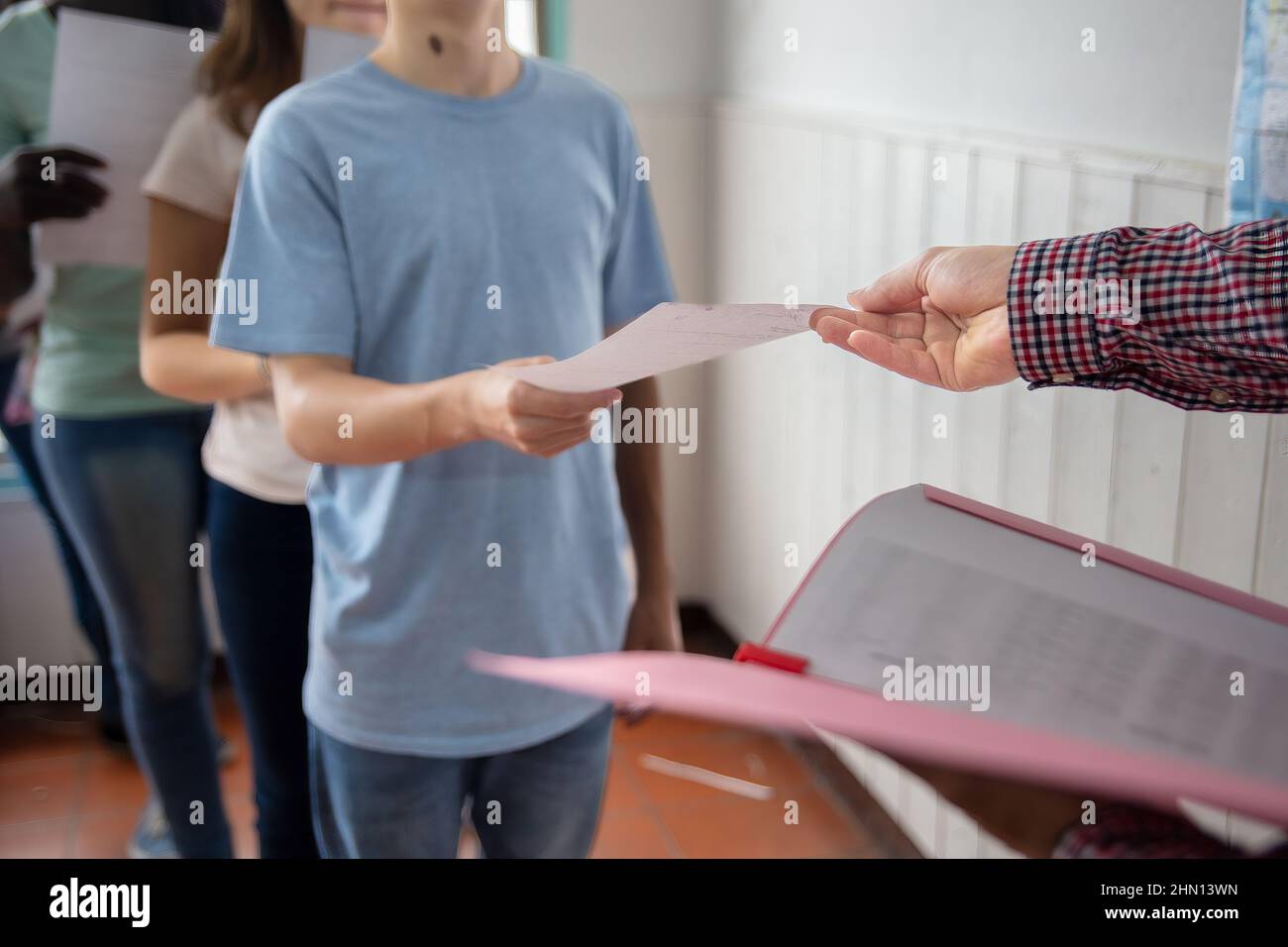 Group of multi ethnic high school students handing in class assignments ...
