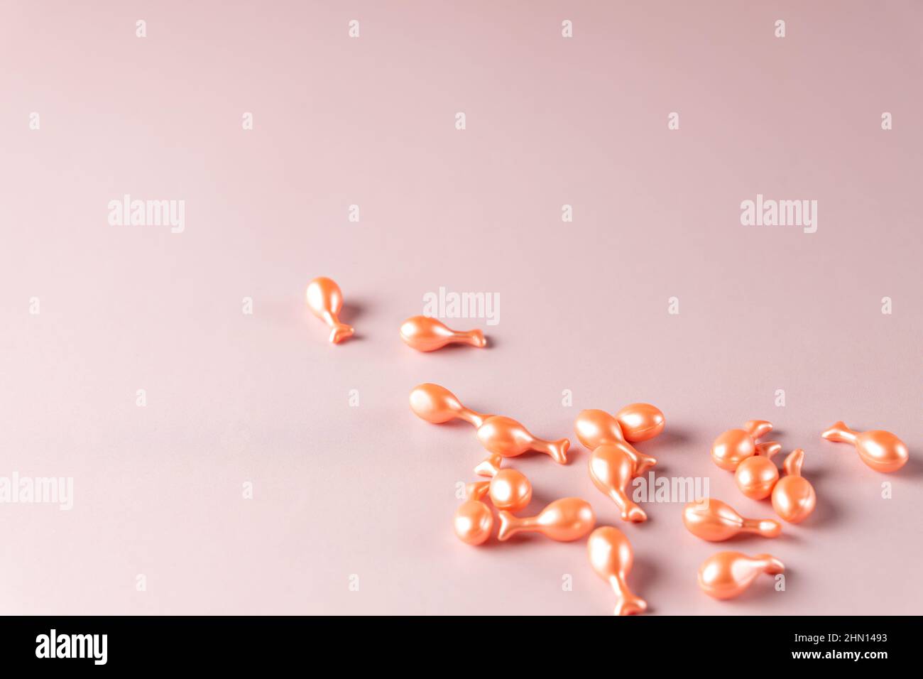 capsules with a cream or serum for face treatment on pink background ...