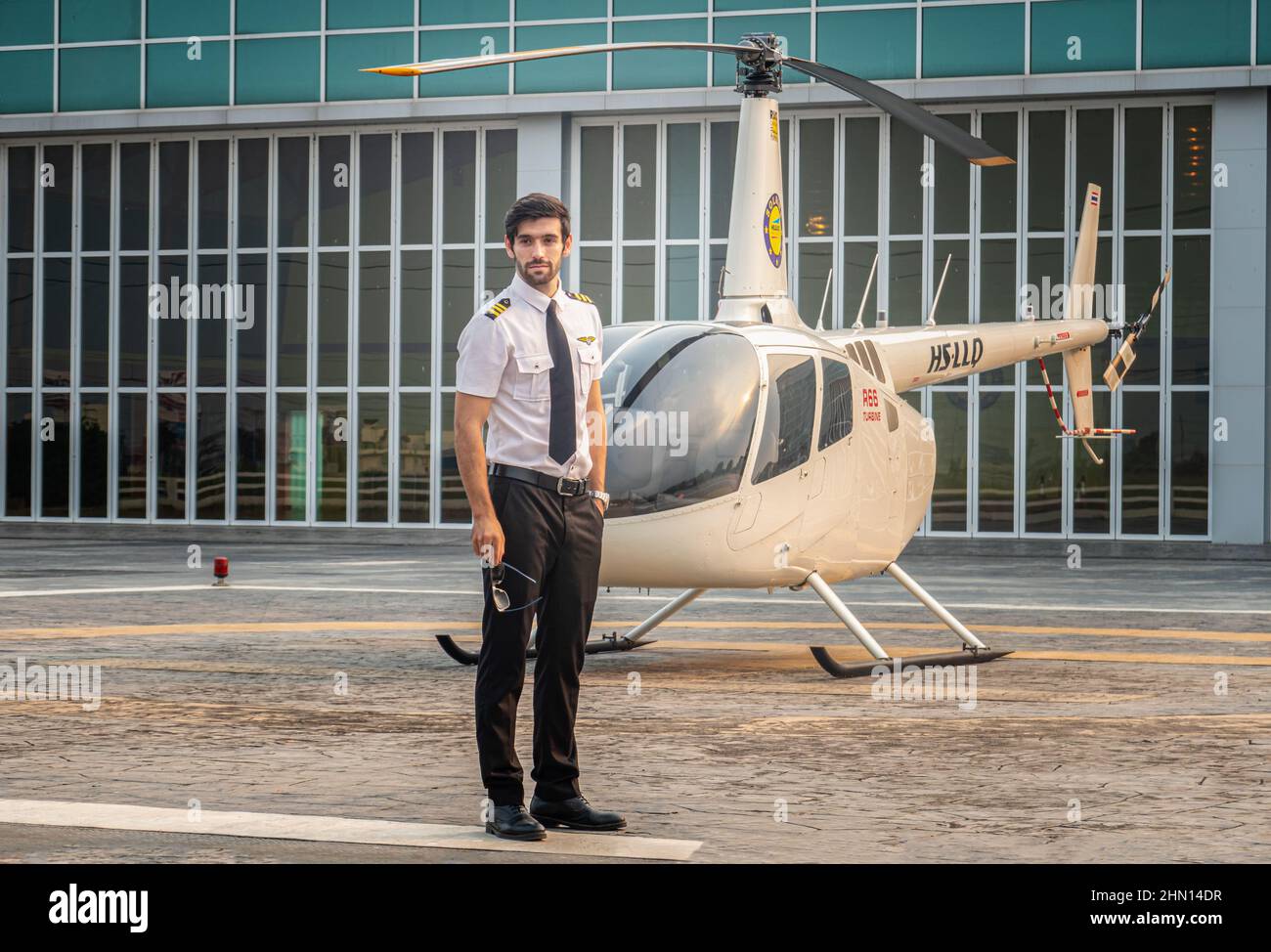 young male on pilot uniform standing in front of helicopter Stock Photo ...