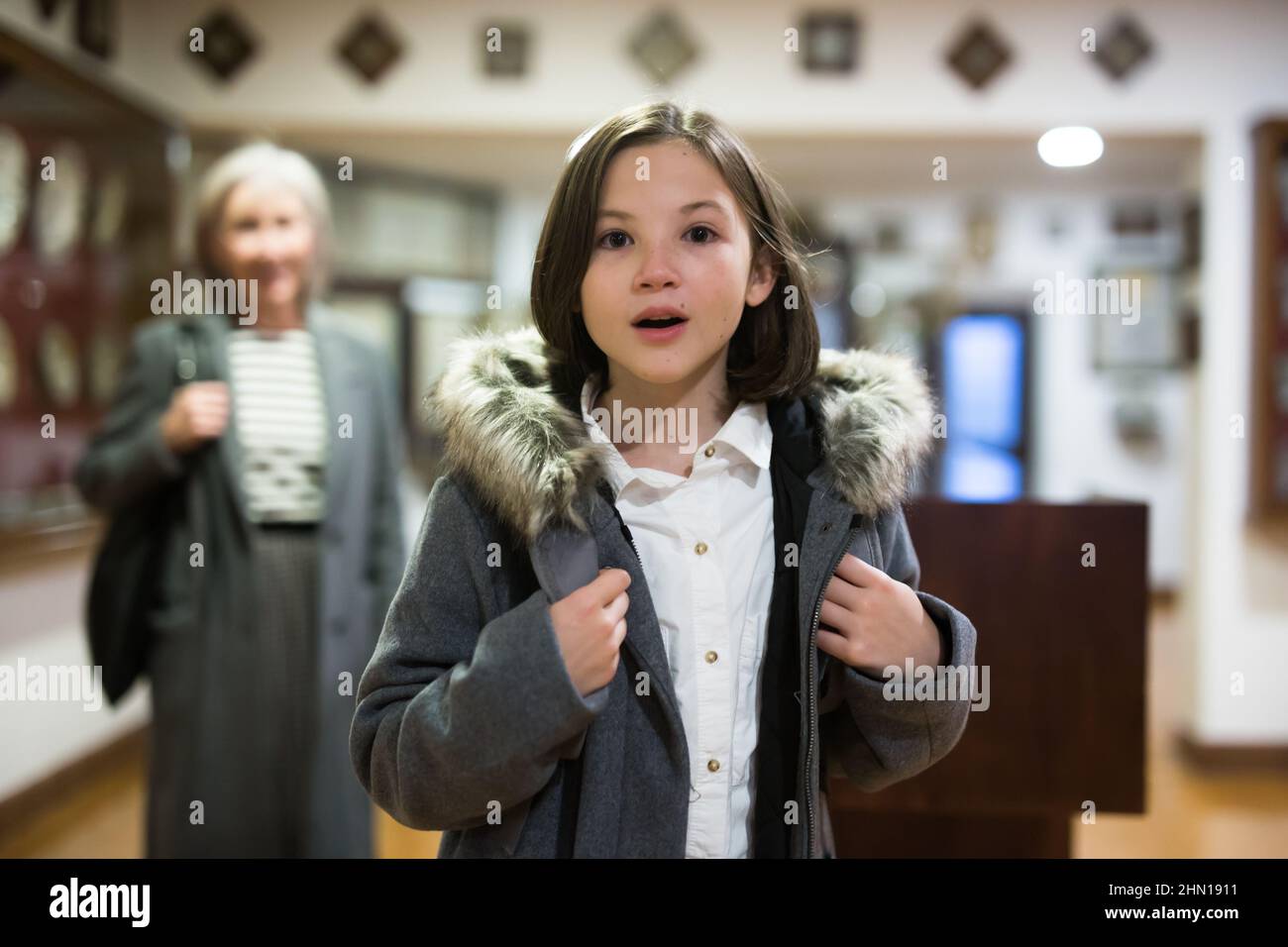 Positive tween girl observing with interest exhibition in art gallery ...