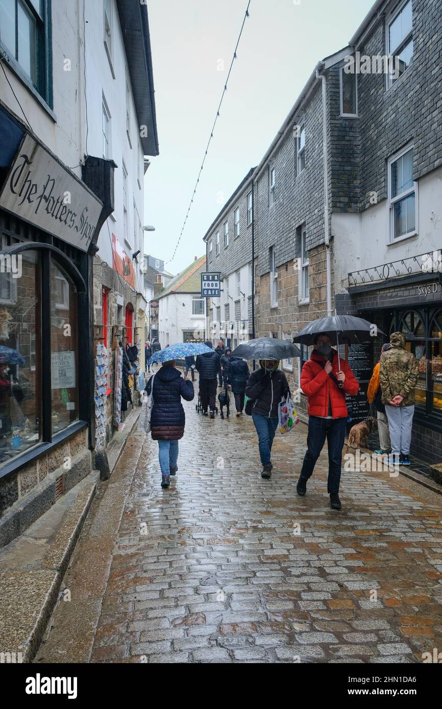 St Ives, UK - February 2022: Shoppers at St Ives Fore Street on a rainy ...