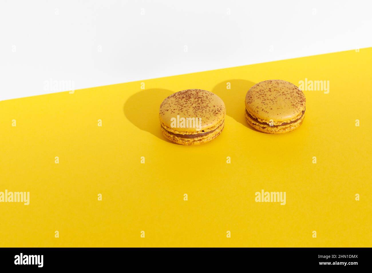 Two Yellow french macaroons on bright yellow and white background ...