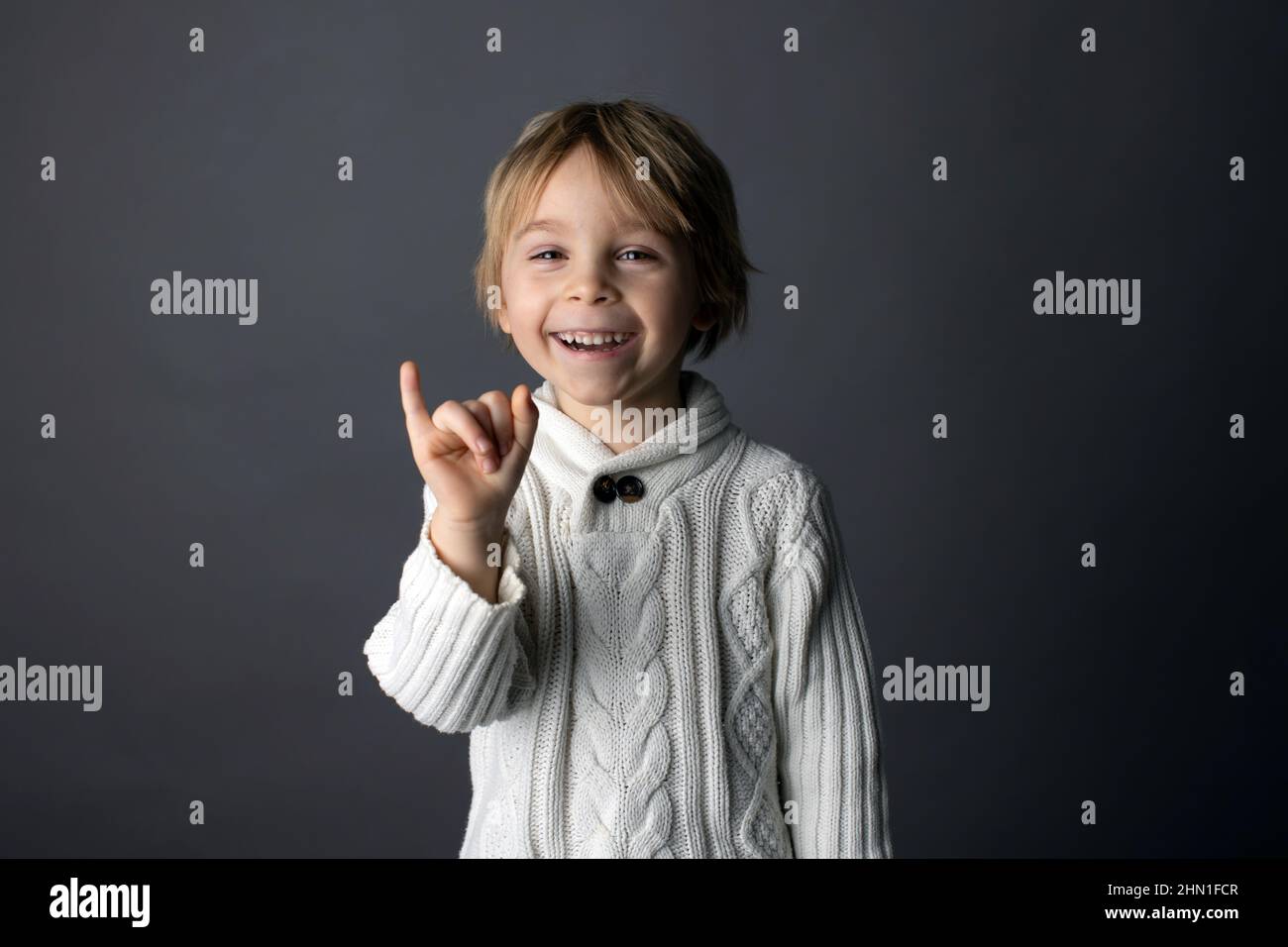 Cute little toddler boy, showing gesture in sign language on gray ...