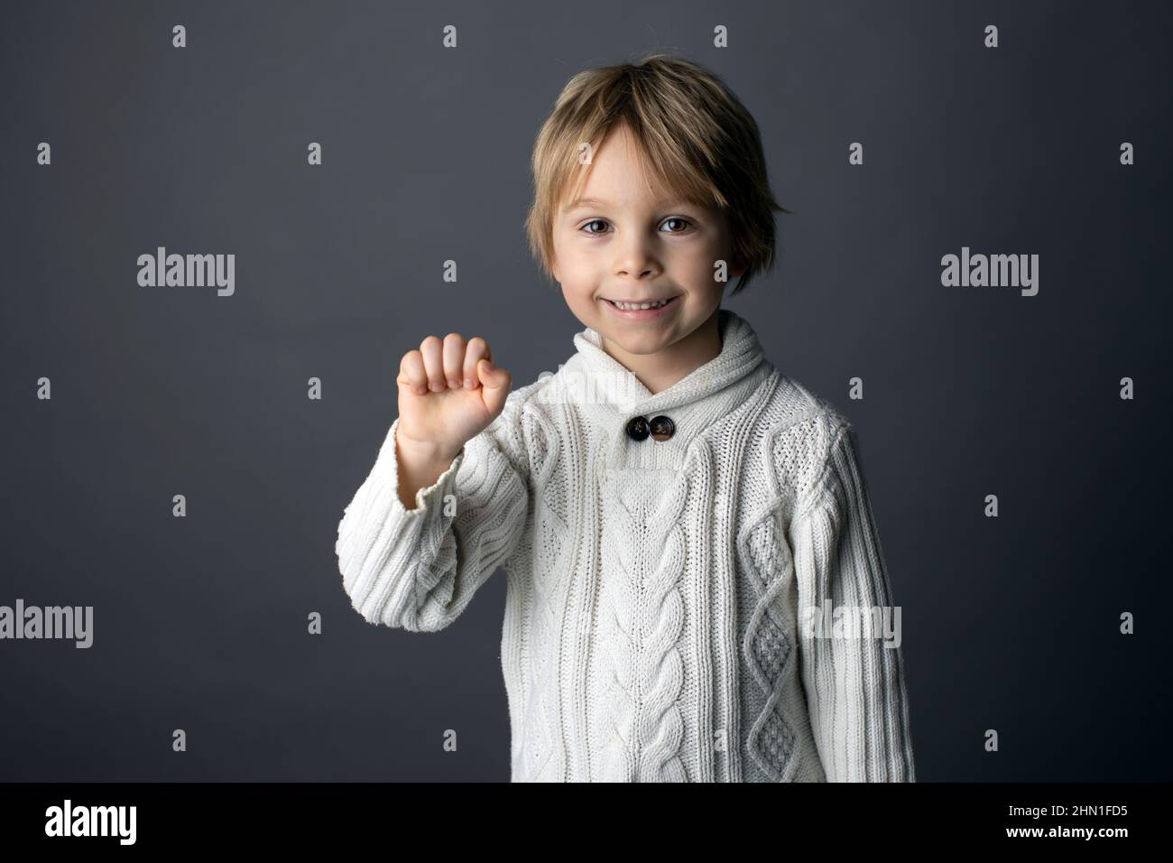 Cute little toddler boy, showing YES gesture in sign language on gray ...
