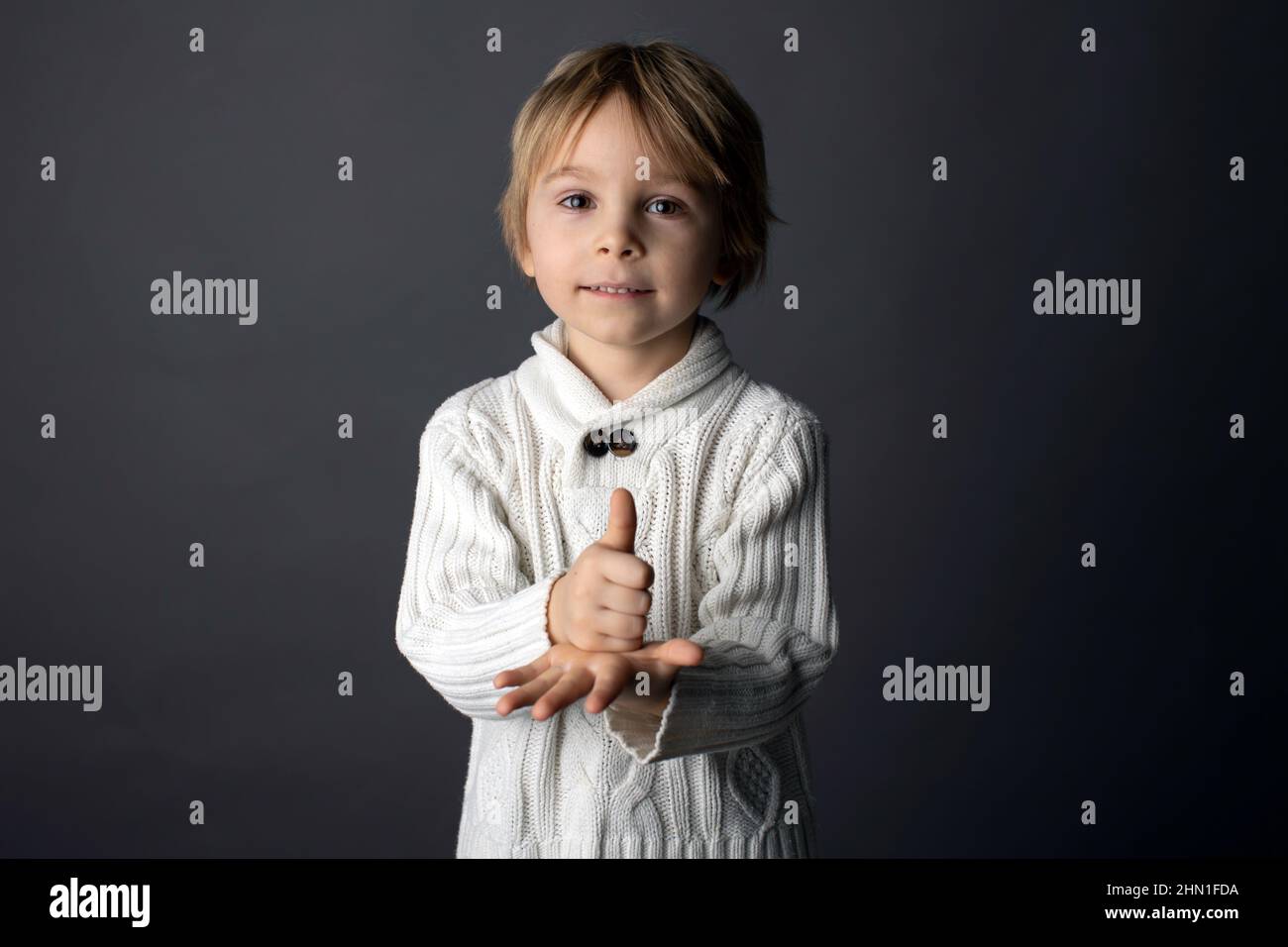 Cute little toddler boy, showing HELP gesture in sign language on gray ...