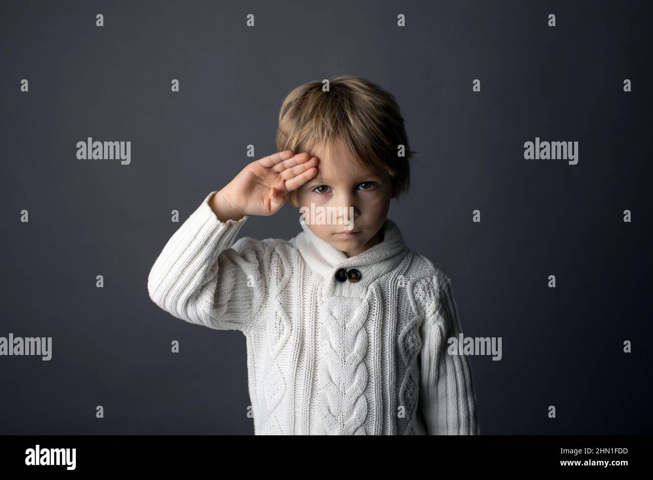 Cute little toddler boy, showing HELLO gesture in sign language on gray ...