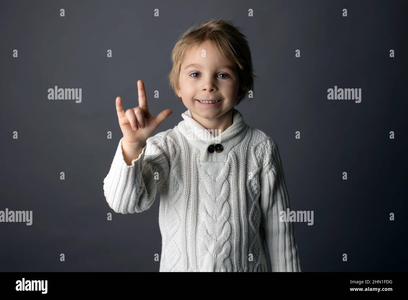 Cute little toddler boy, showing I LOVE YOU gesture in sign language on ...