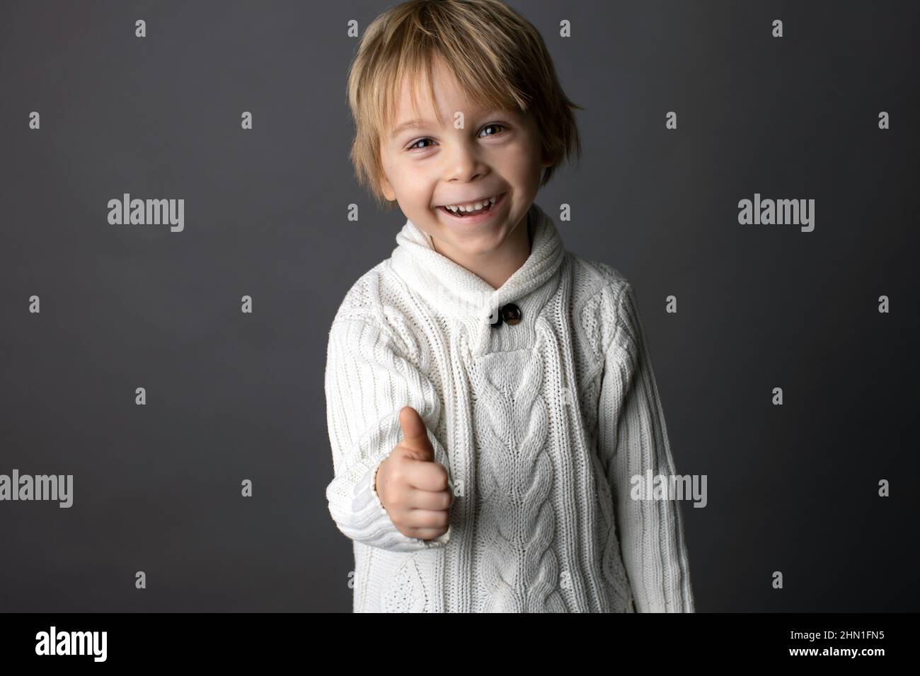 Cute little toddler boy, showing YES gesture in sign language on gray ...