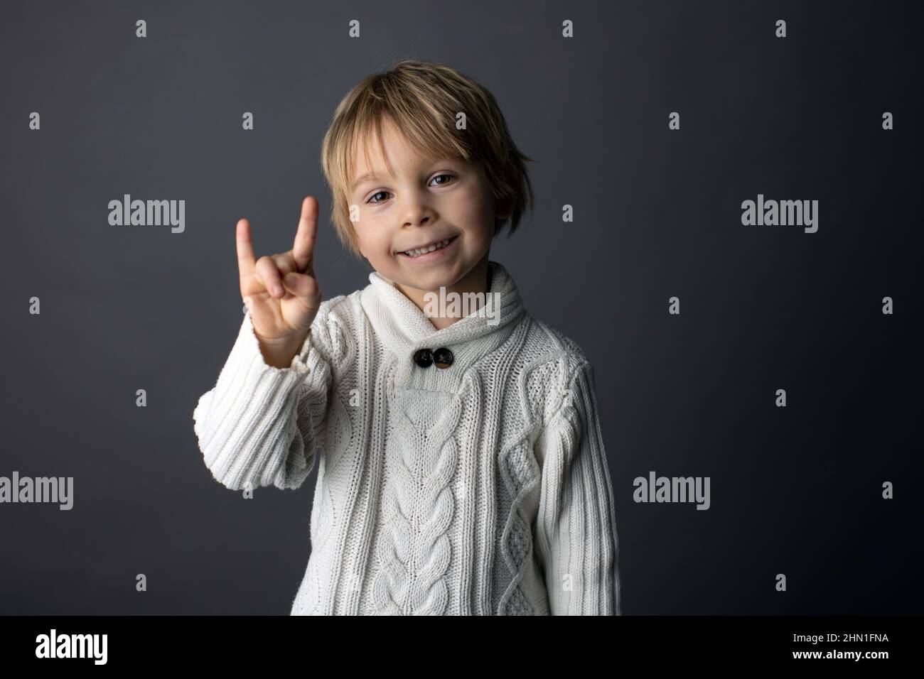 Cute little toddler boy, showing gesture in sign language on gray ...