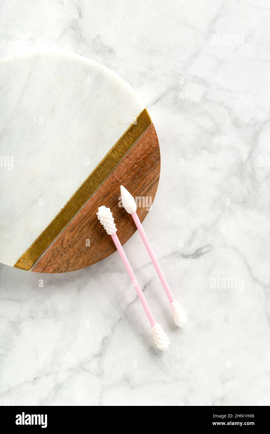 Flat lay top view pink reusable silicone swab buds on white marble ...