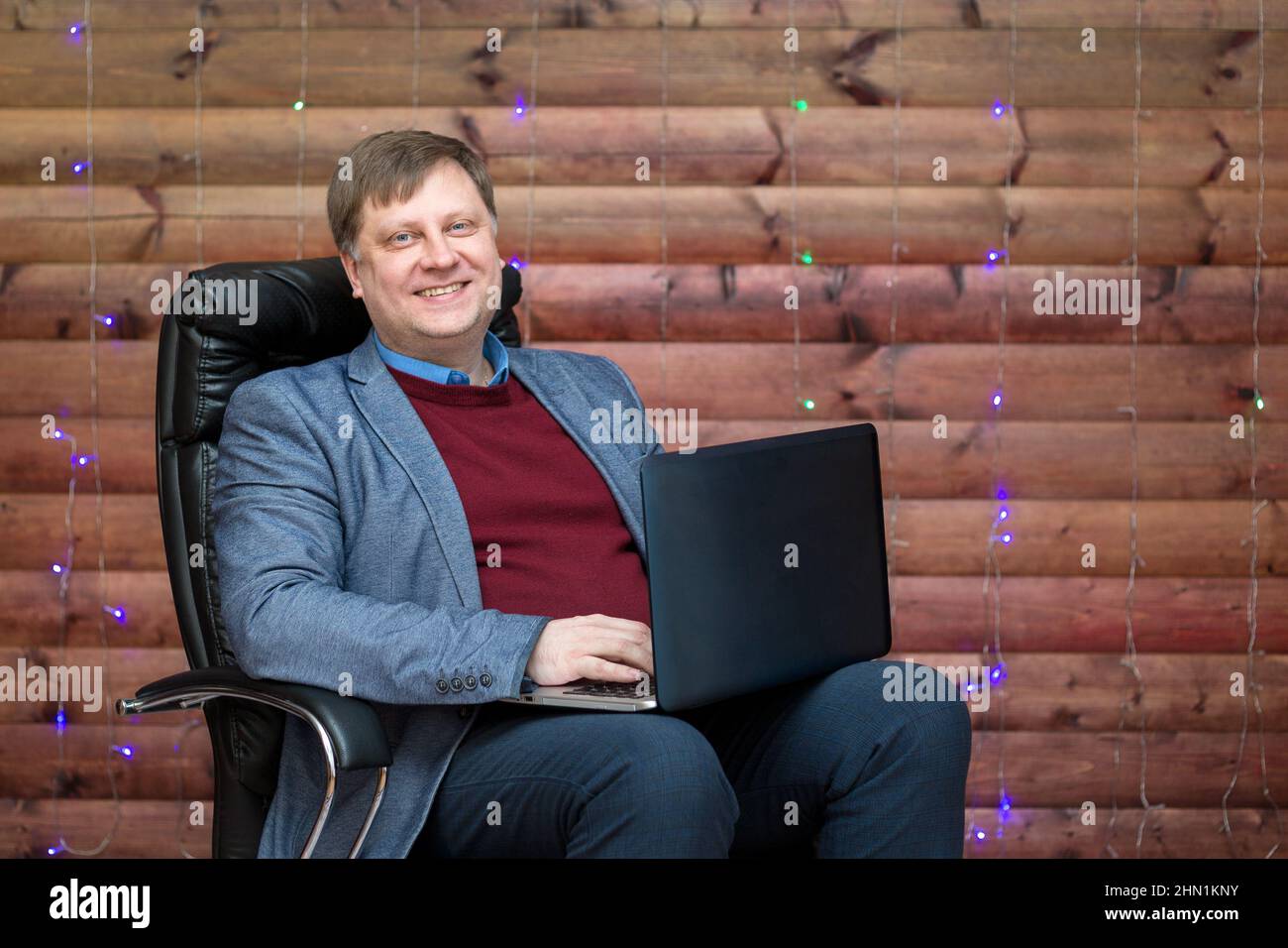 An adult blond man strict gray jacket is sitting in a leather armchair ...