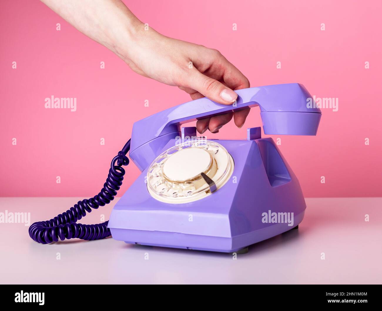 Hand holding retro phone handset, receiver closeup on pink background ...